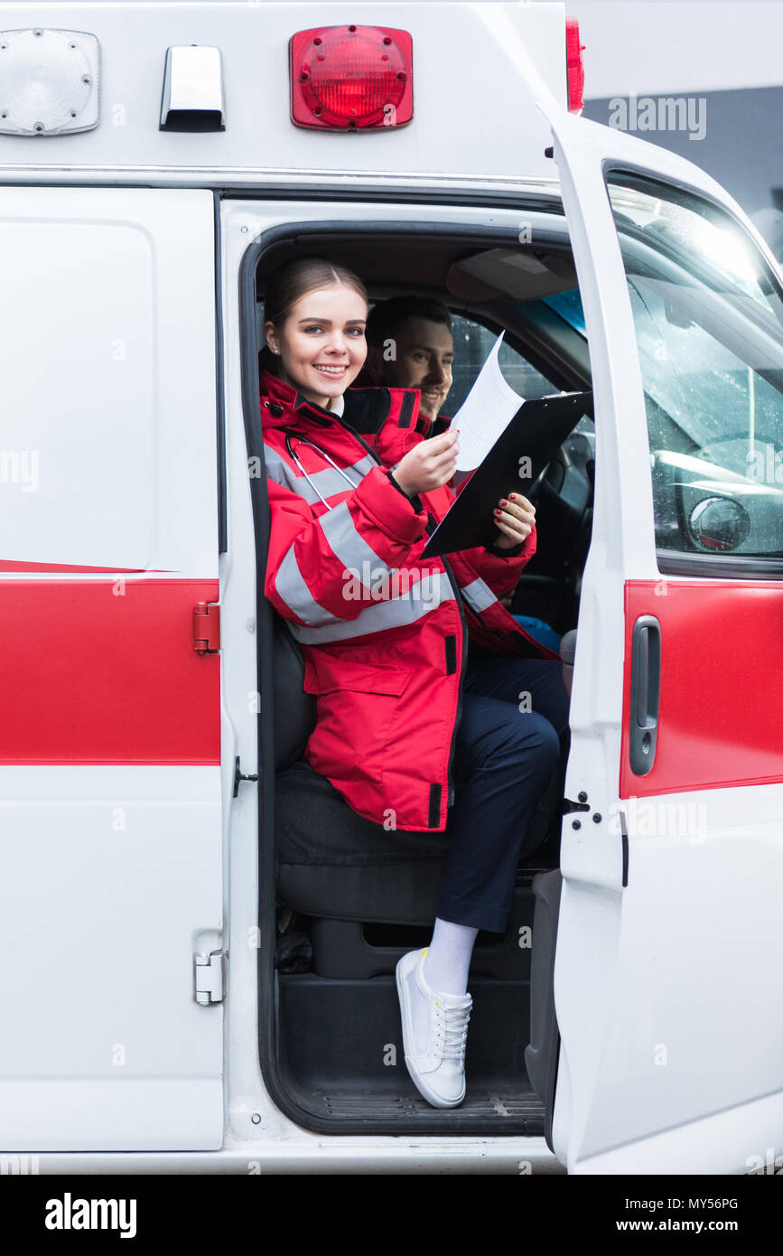 smiling paramedic sitting in ambulance and holding clipboard Stock ...