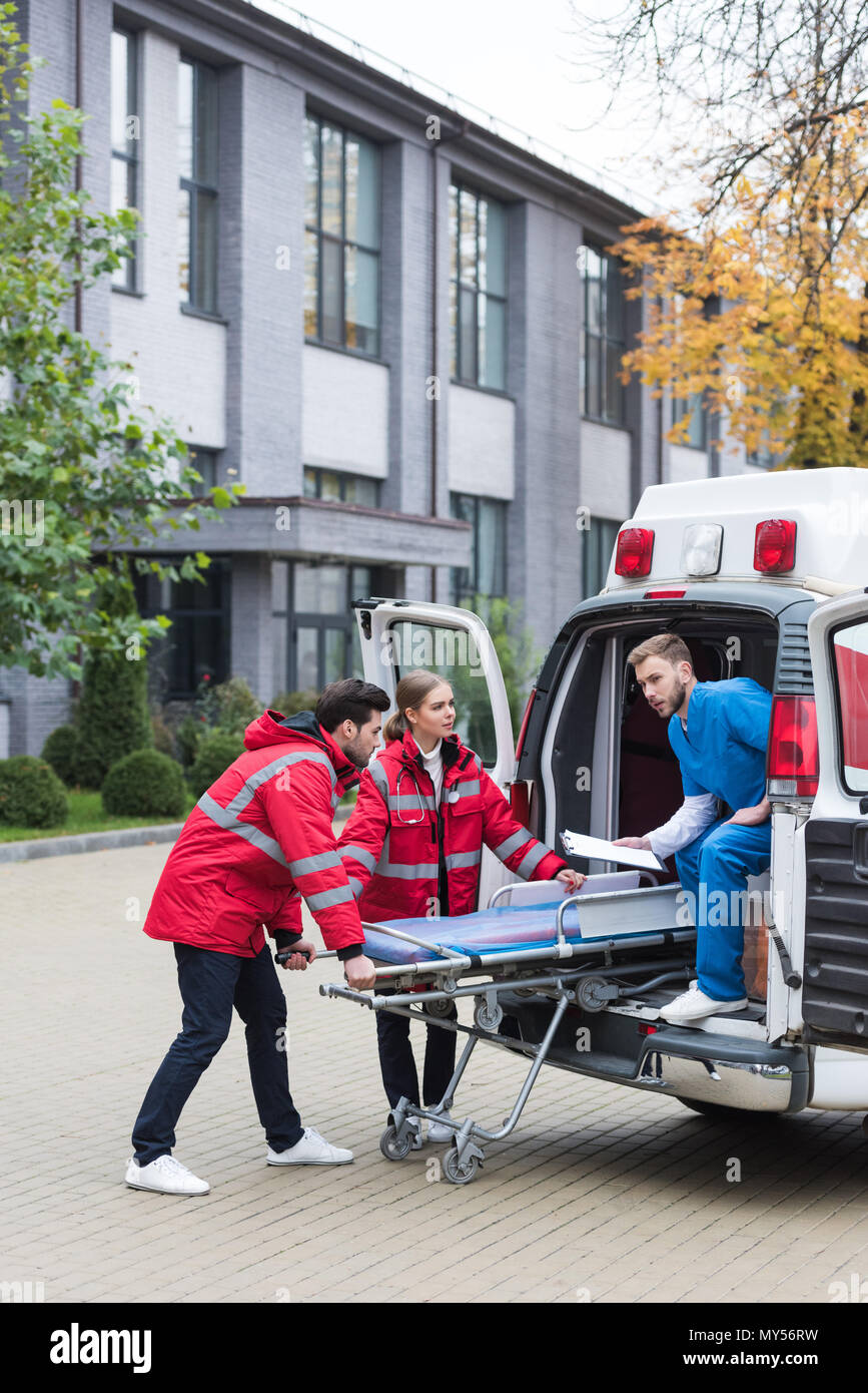 paramedics moving ambulance stretcher into car Stock Photo - Alamy