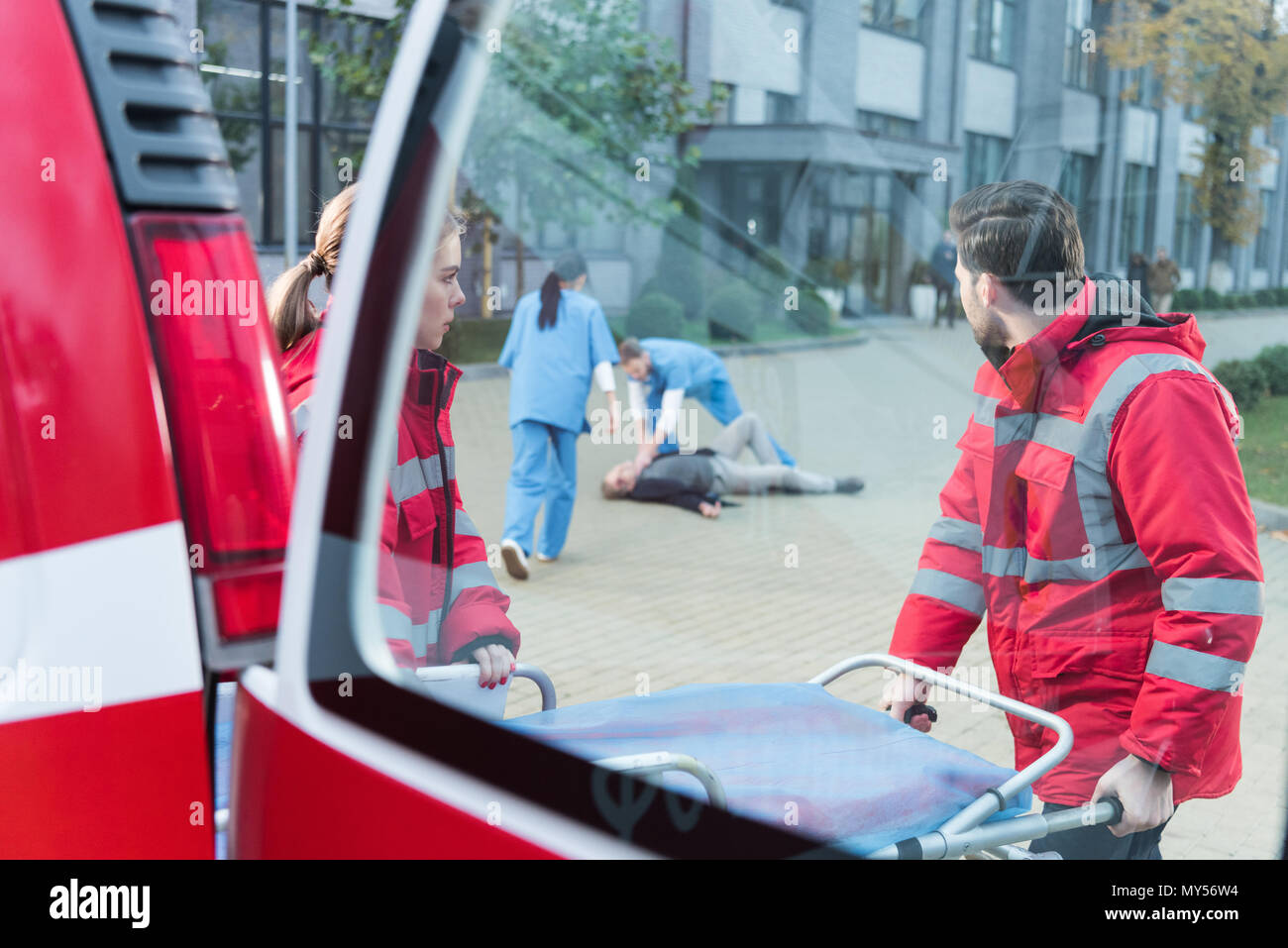 view through window of paramedics helping injured man Stock Photo - Alamy