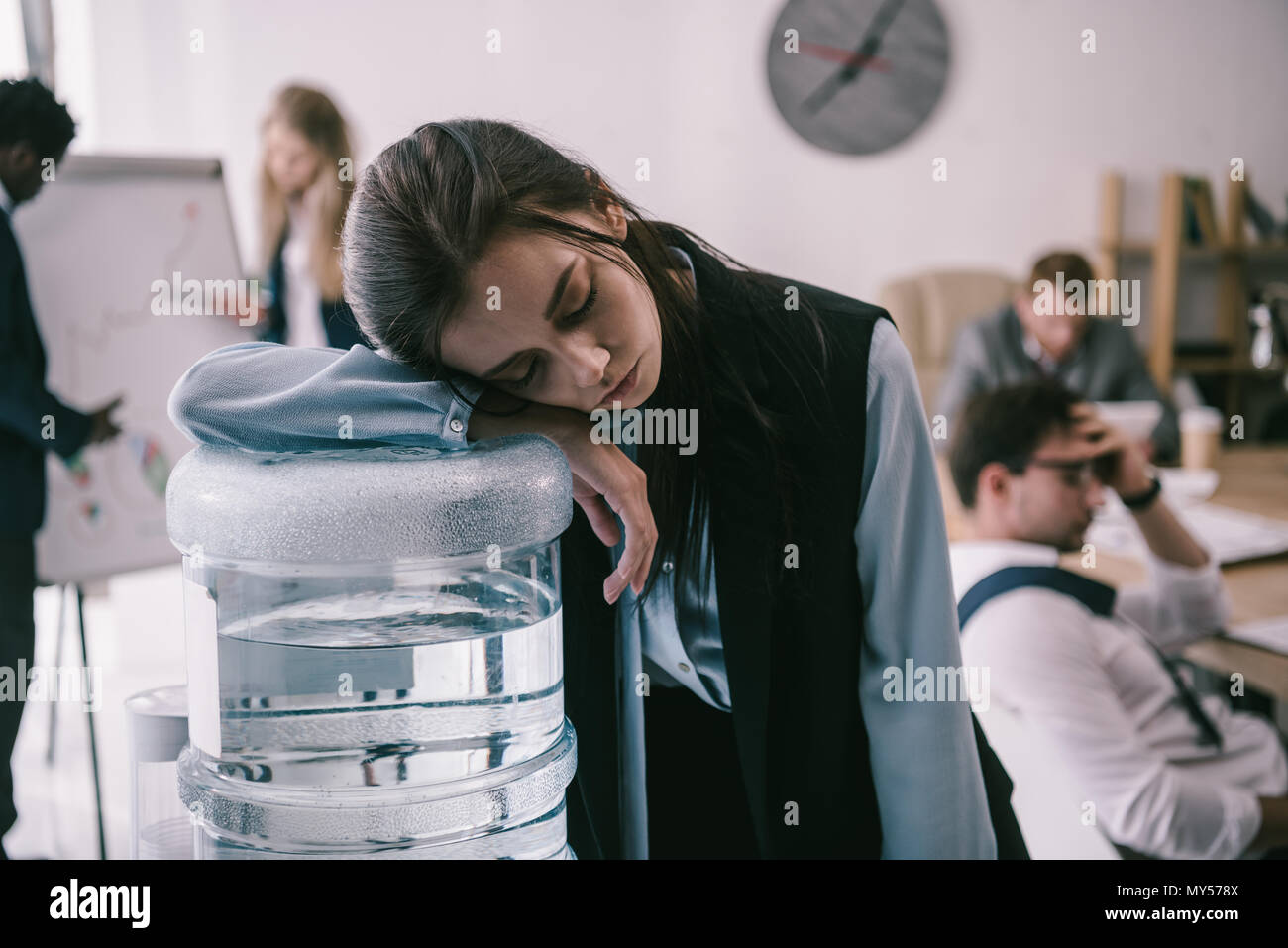 exhausted zombie like manager leaning on water dispenser at office ...