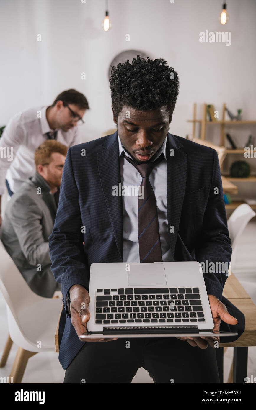shocked young businesswoman looking at laptop while leaning back on ...