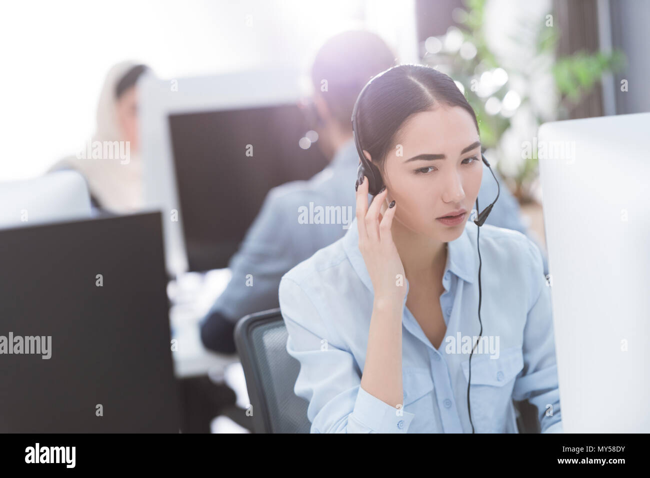 selective focus of concentrated asian call center operator in headset ...