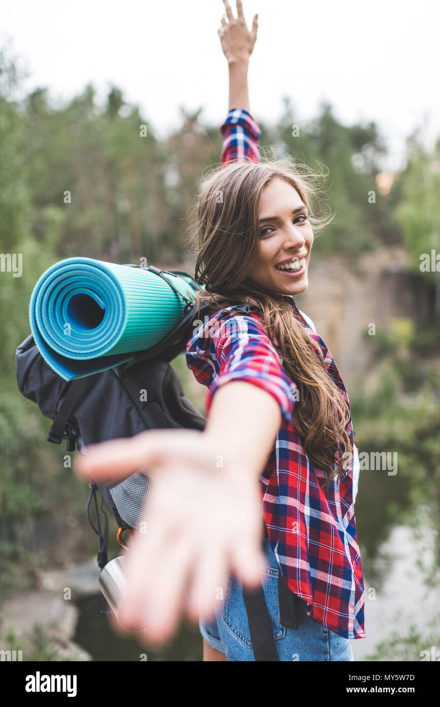 beautiful young woman with trekking backpack stretching hand out to ...