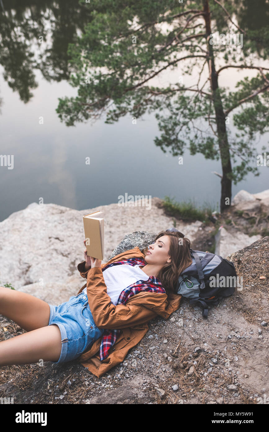 attractive young woman reading book on nature near lake Stock Photo - Alamy