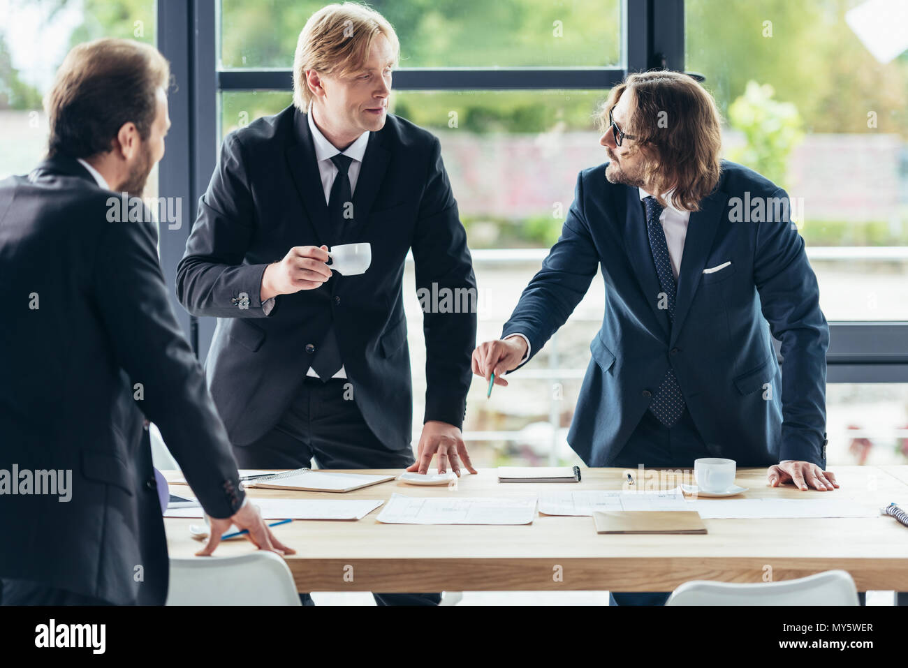 professional middle aged businessmen drinking coffee and working ...