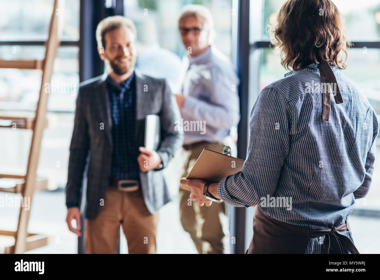 rear view of waiter greeting middle aged businessmen in cafe Stock ...