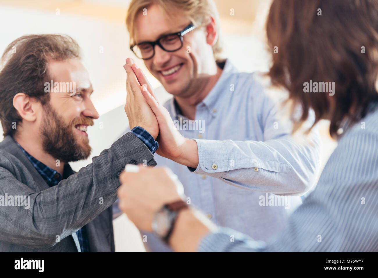 close-up view of cheerful middle aged men giving high five each other ...
