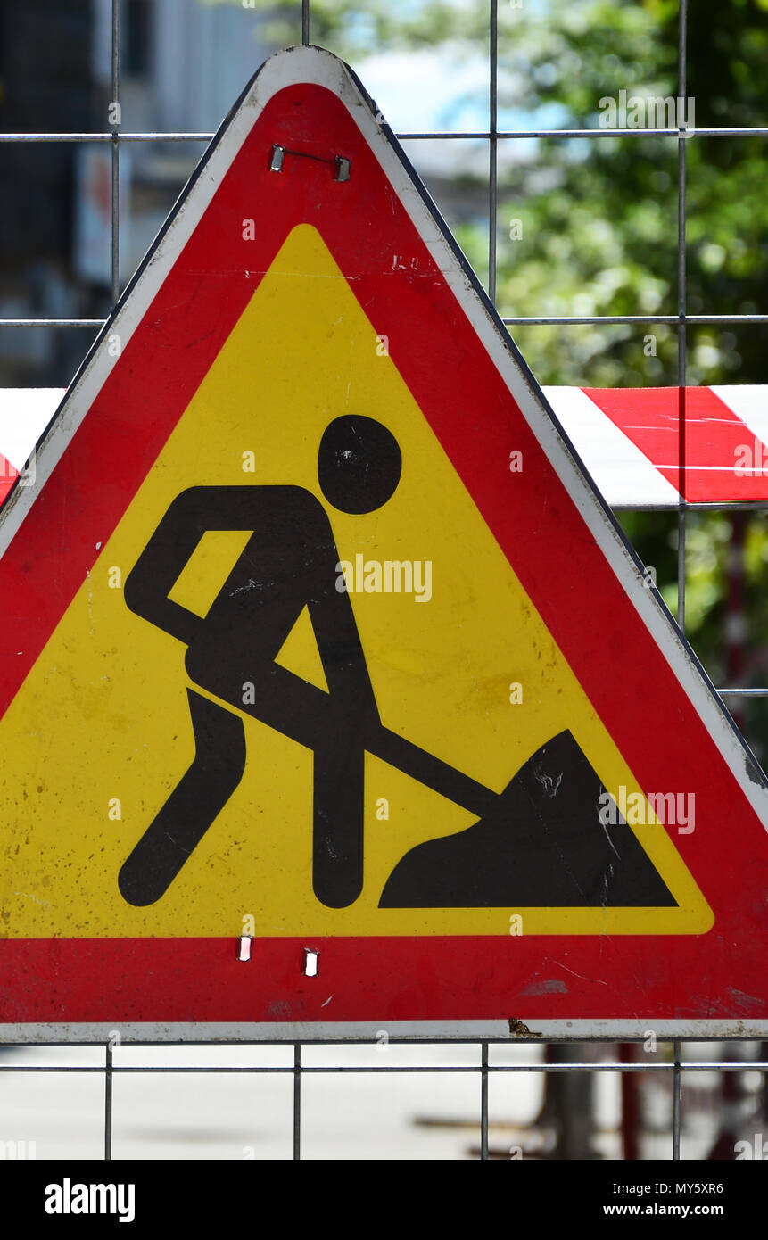 The warning sign "under construction" is attached to a metal mesh fence ...