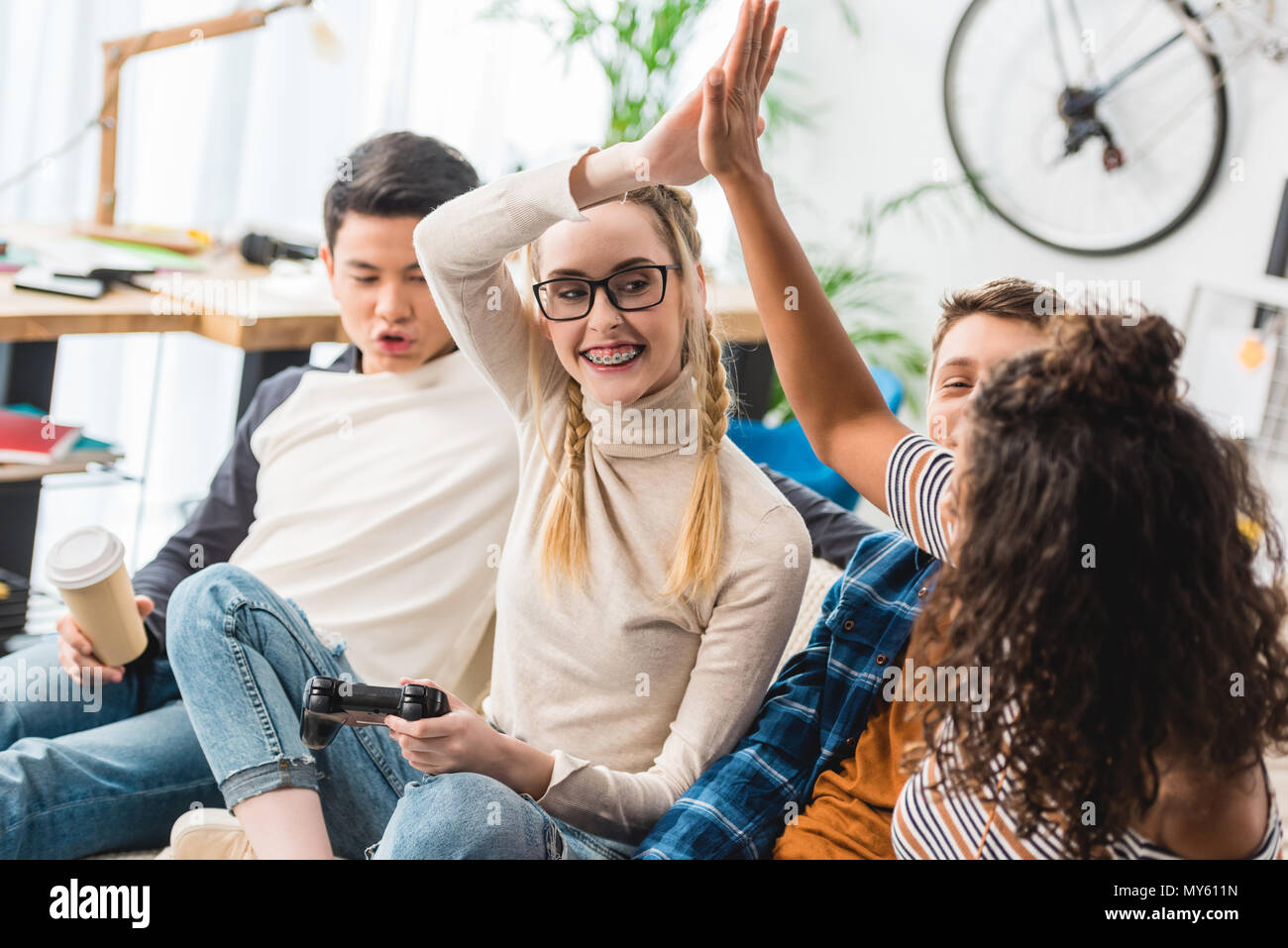girls giving high five for winning boys in video game Stock Photo - Alamy