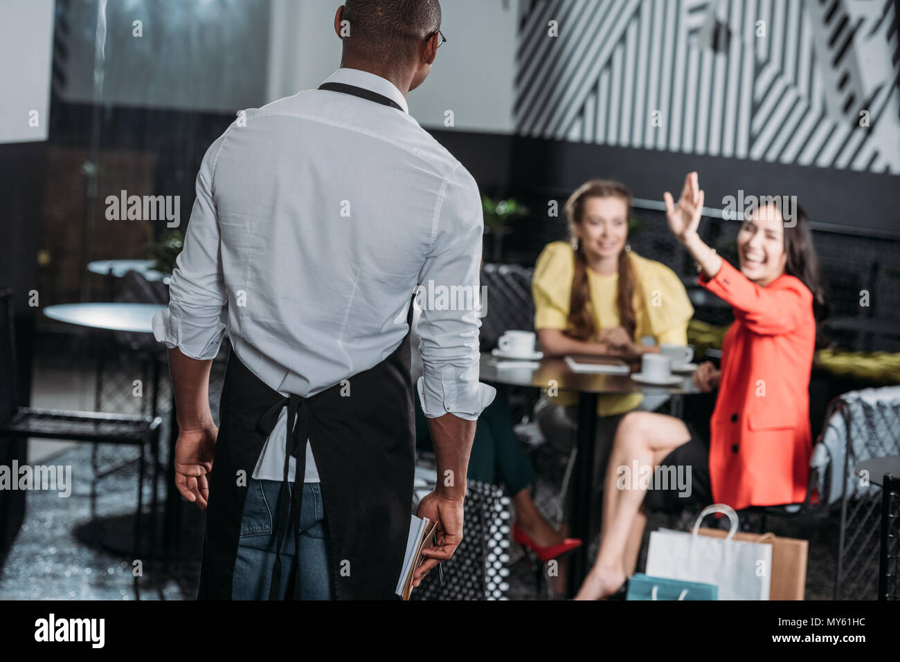 happy young women waving to waiter at cafe Stock Photo - Alamy