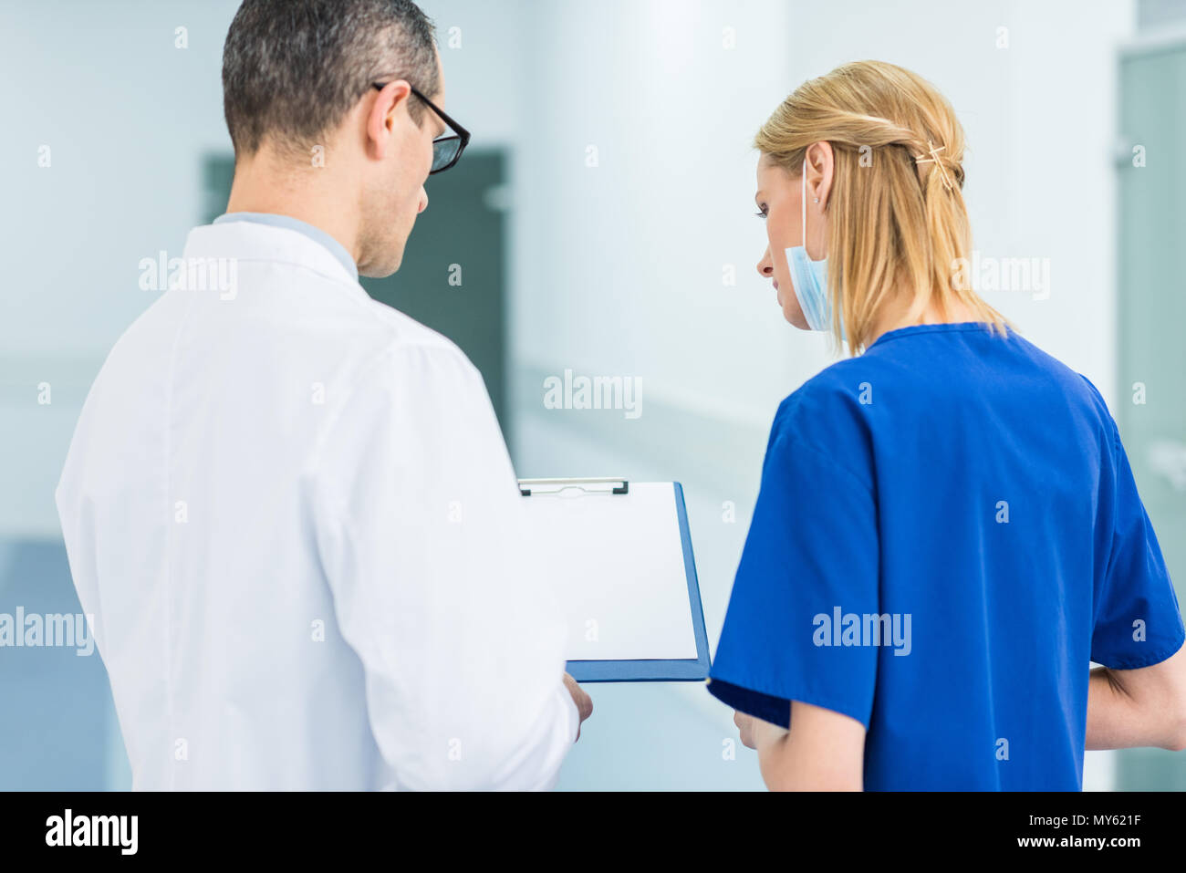 back view of doctor in white coat and female surgeon discussing ...