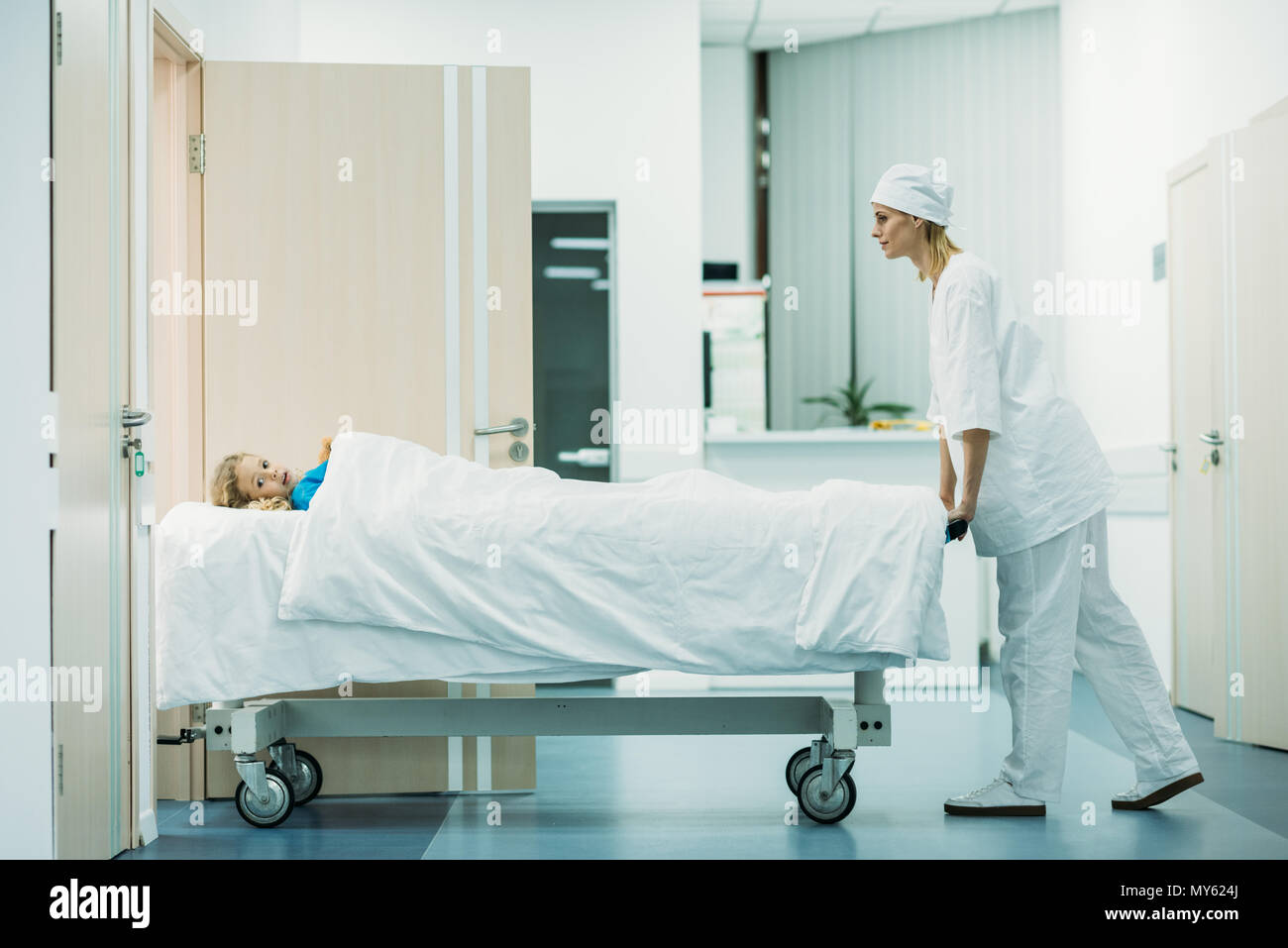 side view of doctor moving preschooler patient on medical stretcher in ...