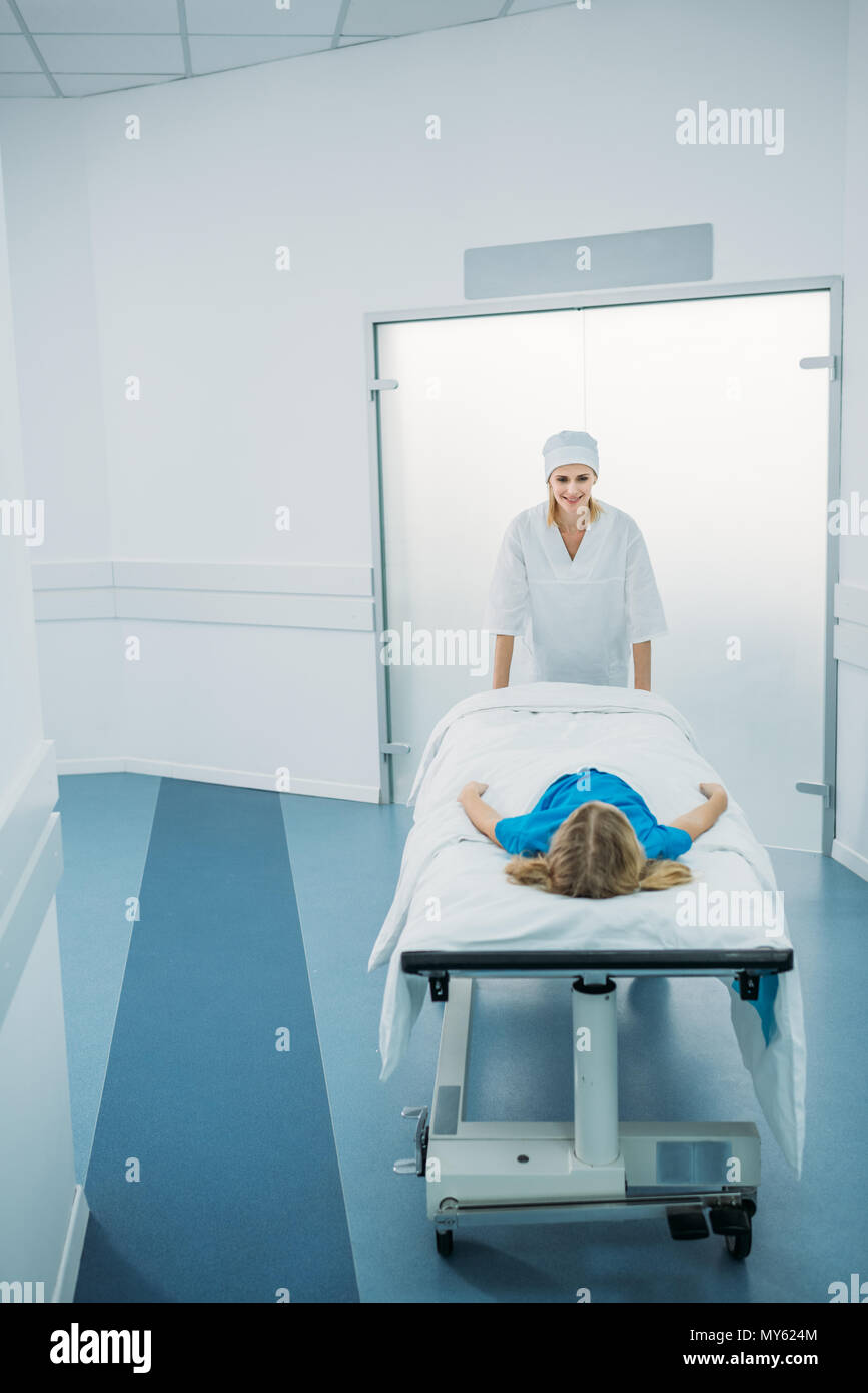 smiling doctor moving preschooler patient on medical stretcher in ...
