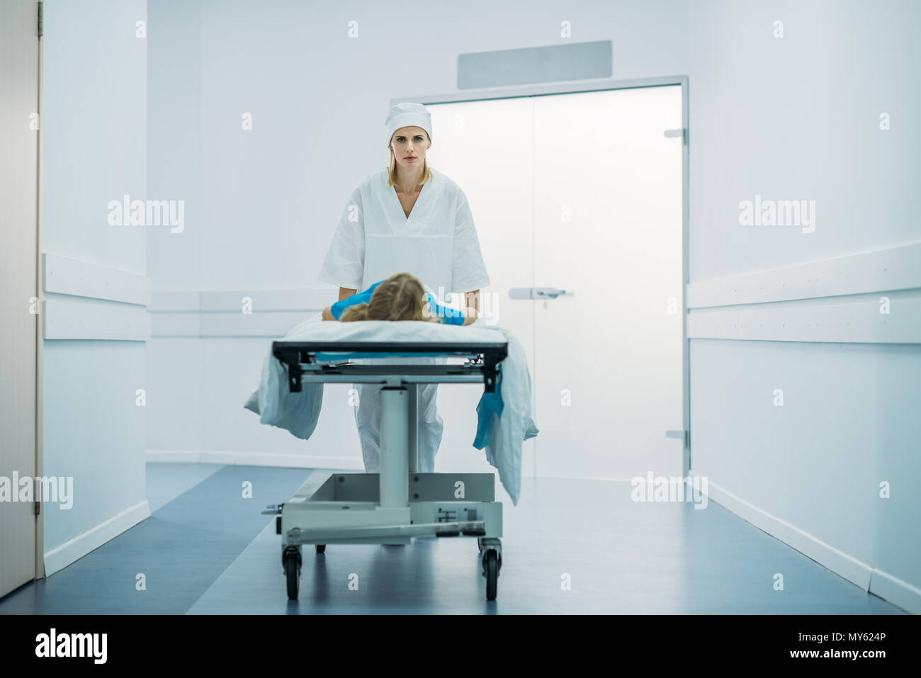 nurse moving preschooler patient on medical stretcher in corridor Stock ...