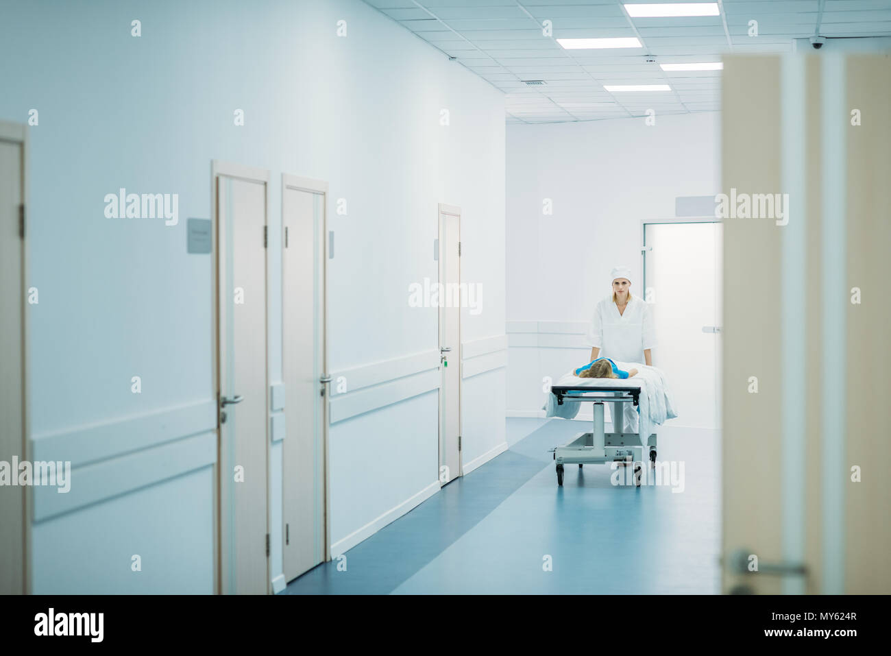 doctor moving preschooler patient on medical stretcher in corridor ...