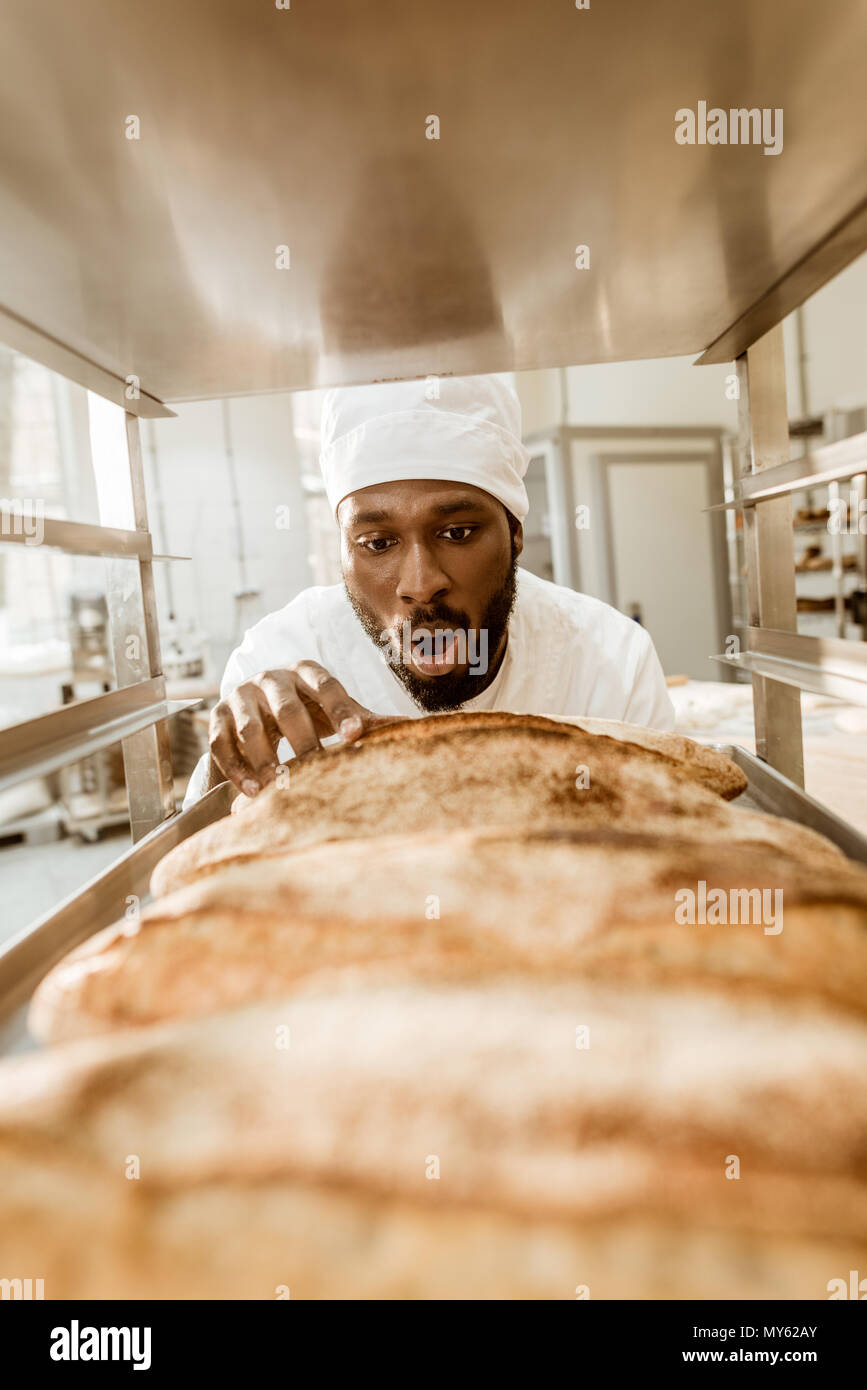 shocked african american baker looking at fresh loaves of bread on ...