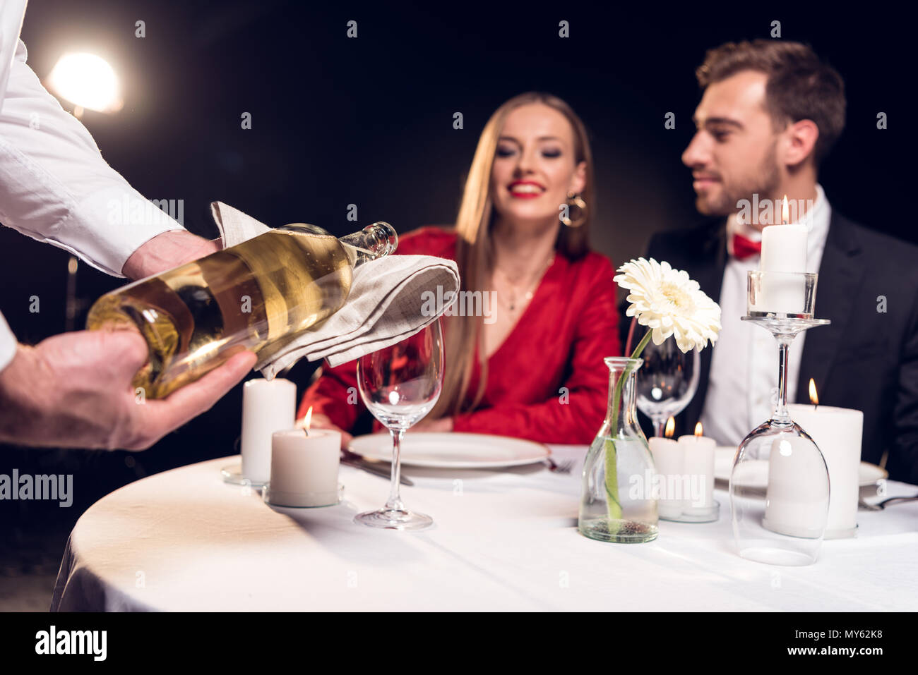 waiter pouring wine while couple having romantic date in restaurant on ...