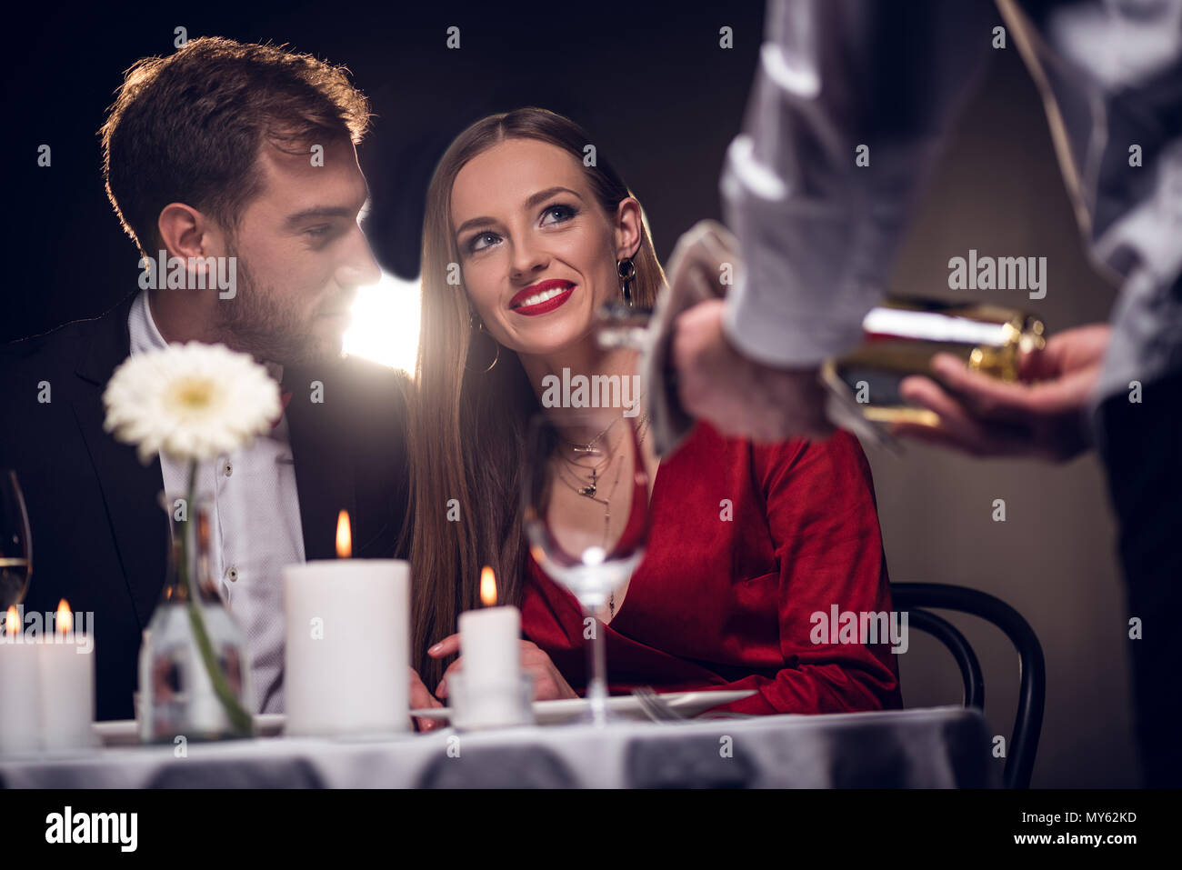 waiter pouring wine while happy couple having romantic date in ...