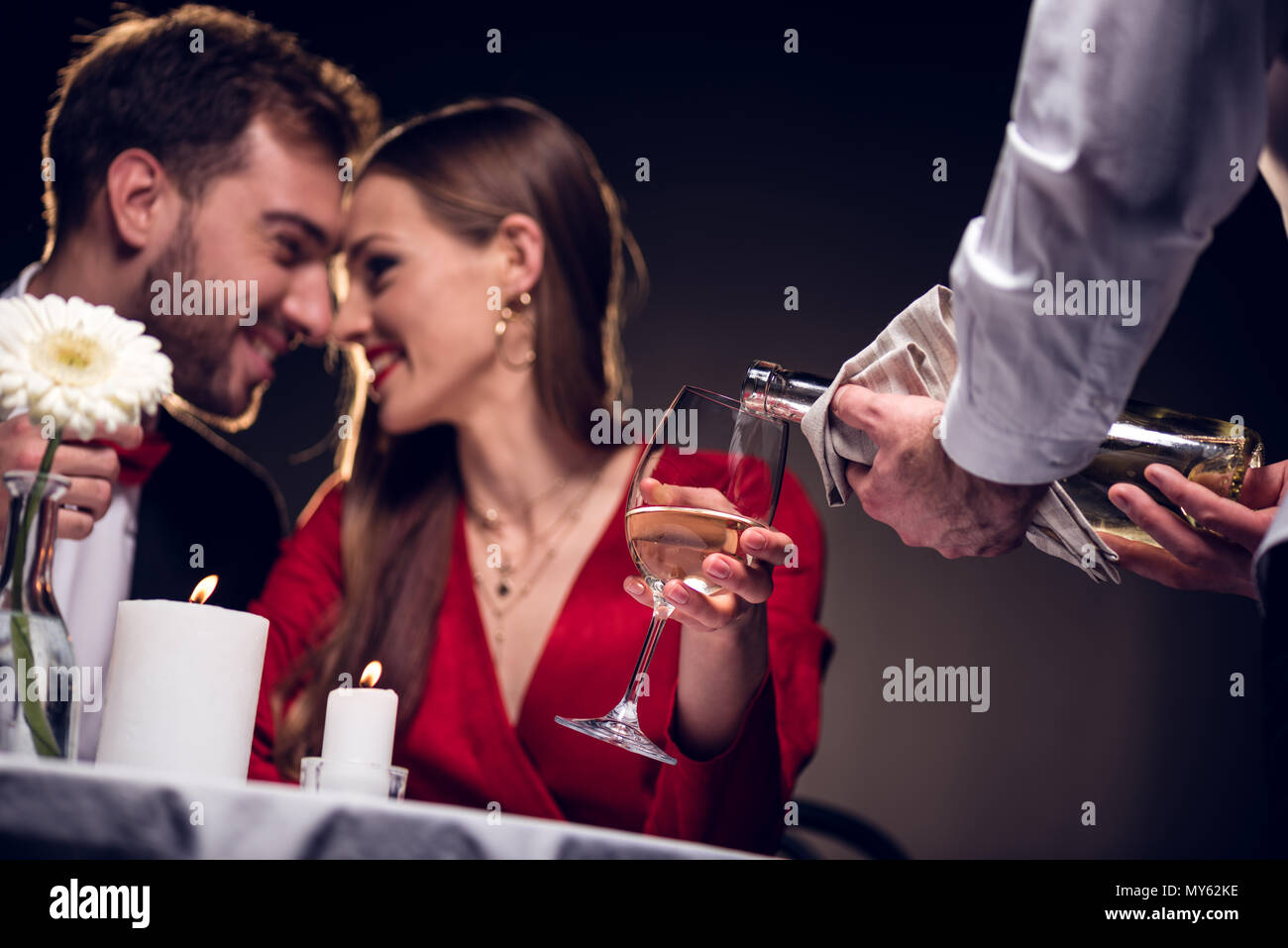 waiter pouring wine while smiling couple having romantic date in ...