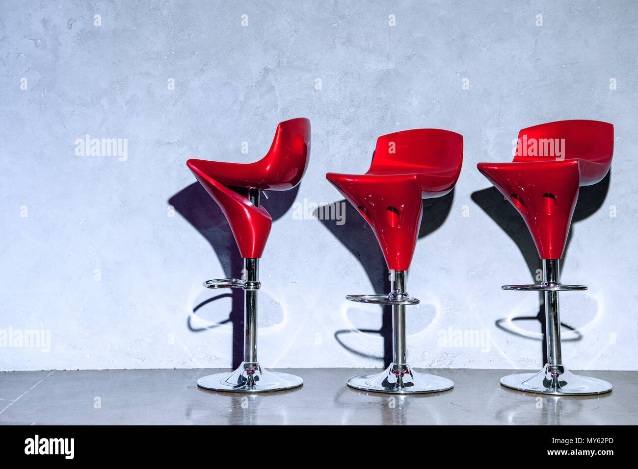 three red empty bar stools near grey wall Stock Photo - Alamy