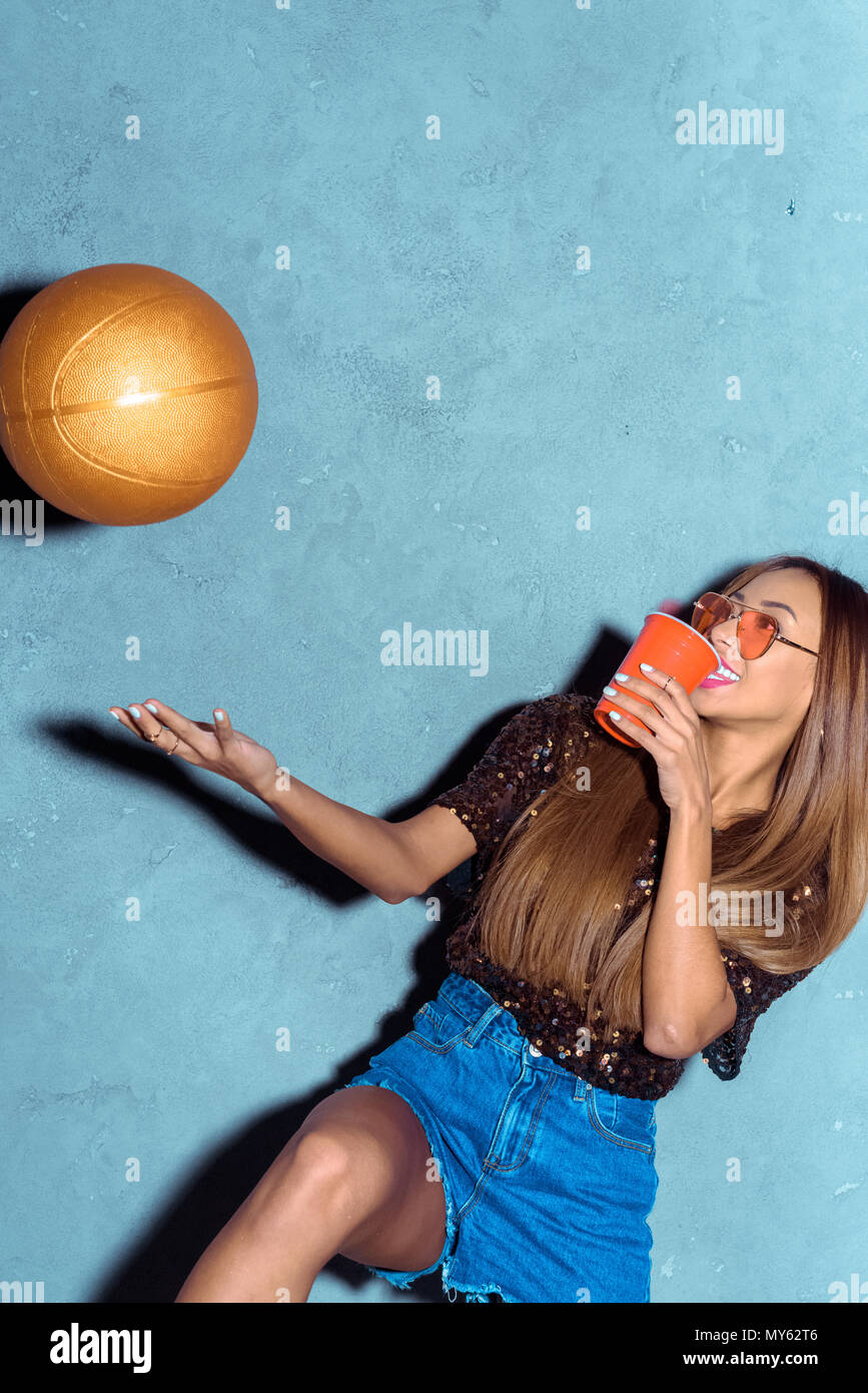african american woman with disposable cup throwing golden basketball ...