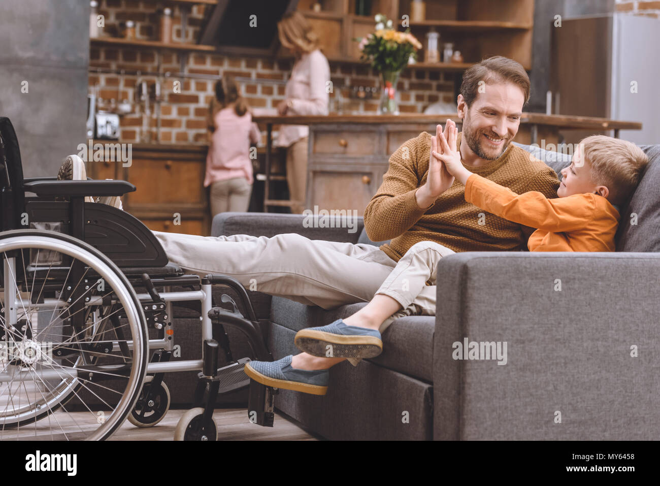 happy little son with smiling disabled father giving high five and ...