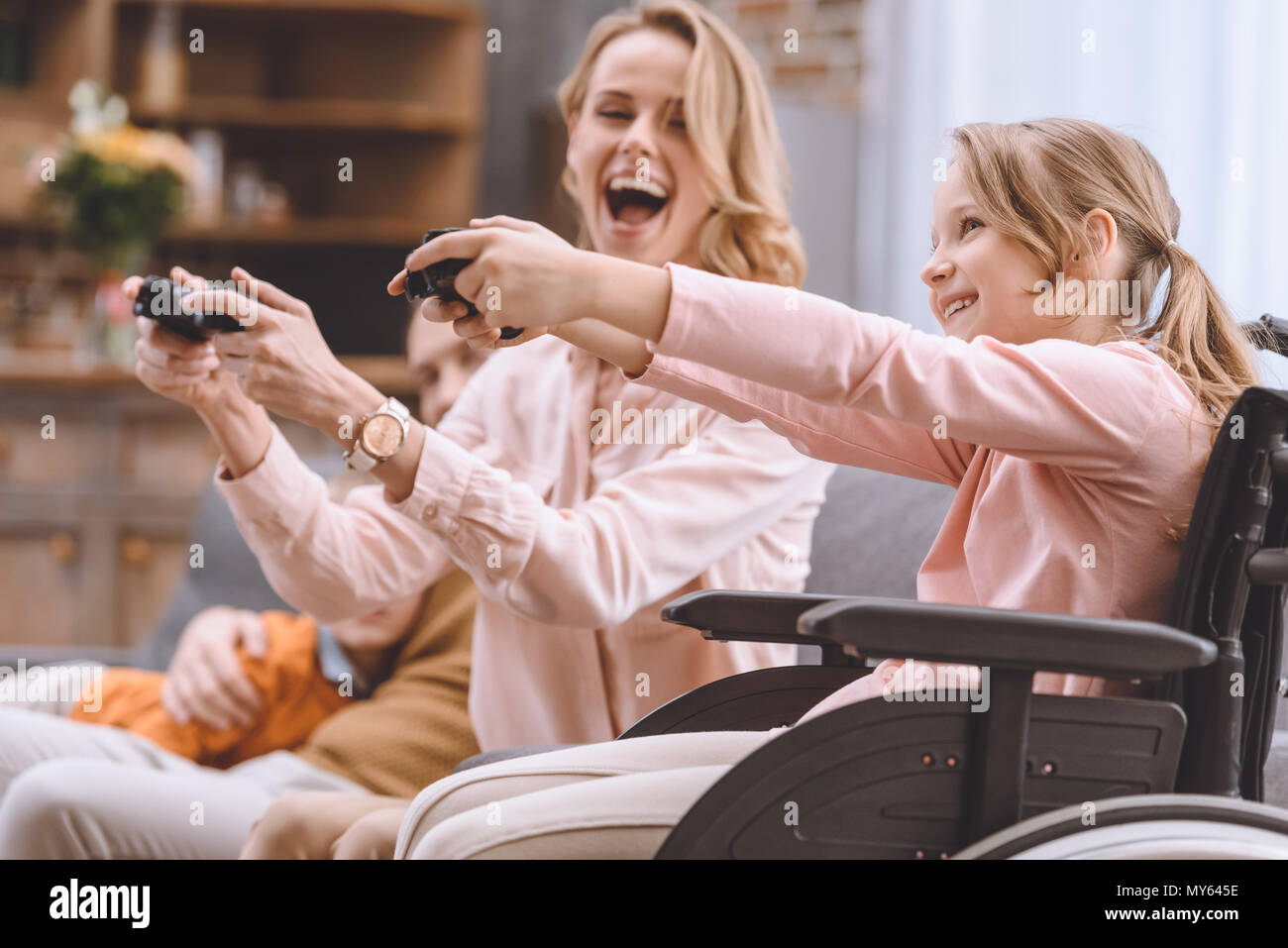 cheerful family with disabled child in wheelchair playing with ...