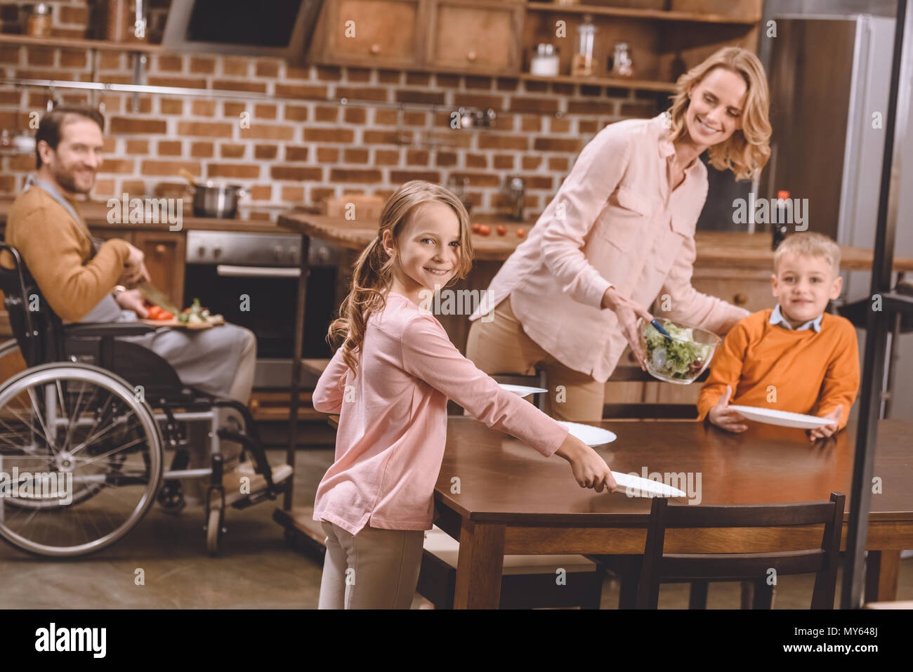 happy children with mother serving table for dinner while disabled ...