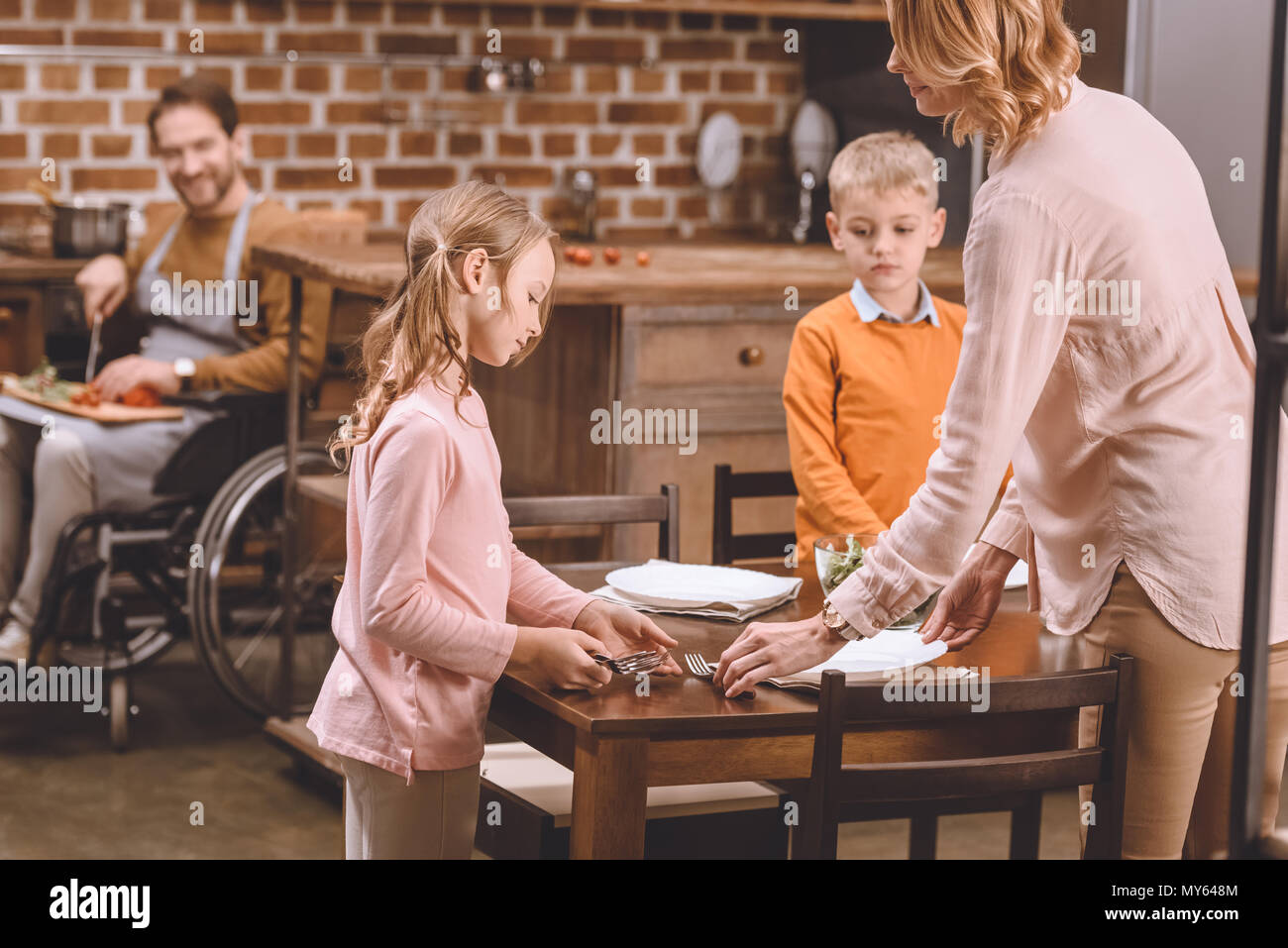 siblings with mother serving table for dinner while disabled father in ...