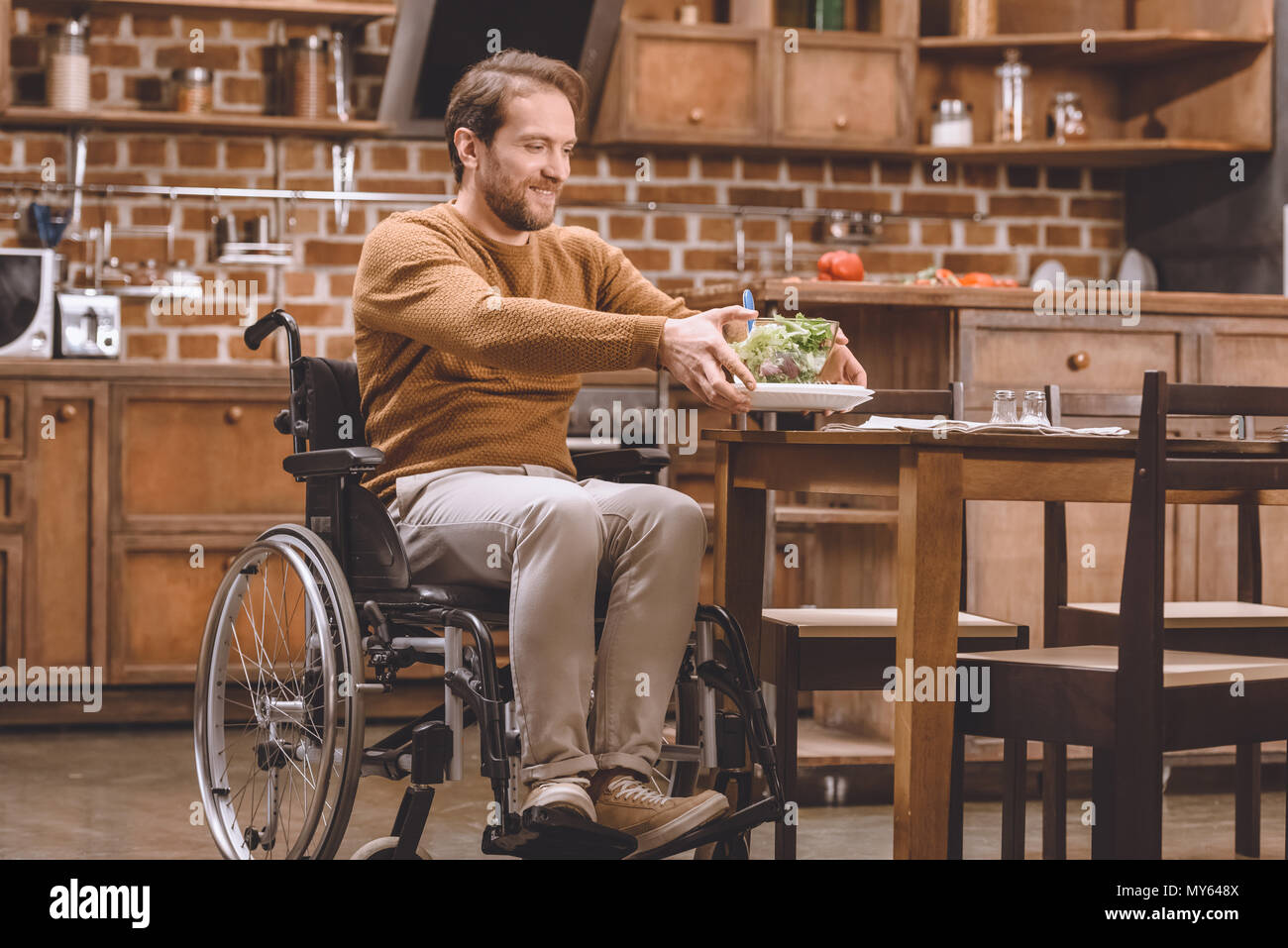 happy disabled man in wheelchair holding glass bowl of vegetable salad ...