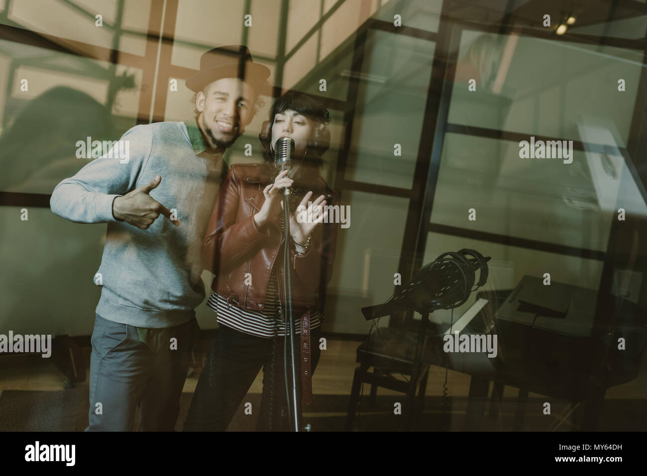 young singers couple recording song behind glass at studio Stock Photo ...