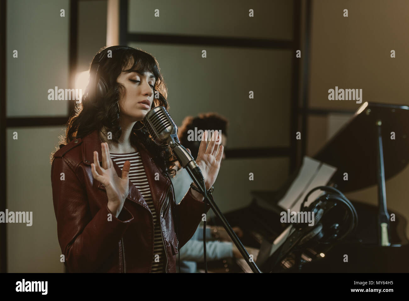 beautiful young female singer performing song with pianist blurred on ...