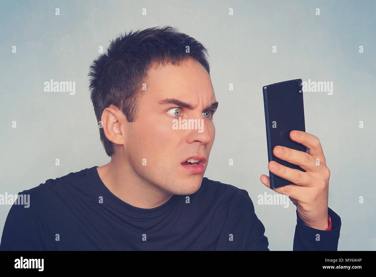 Disgusted man reading a text message. guy looks at the smartphone ...