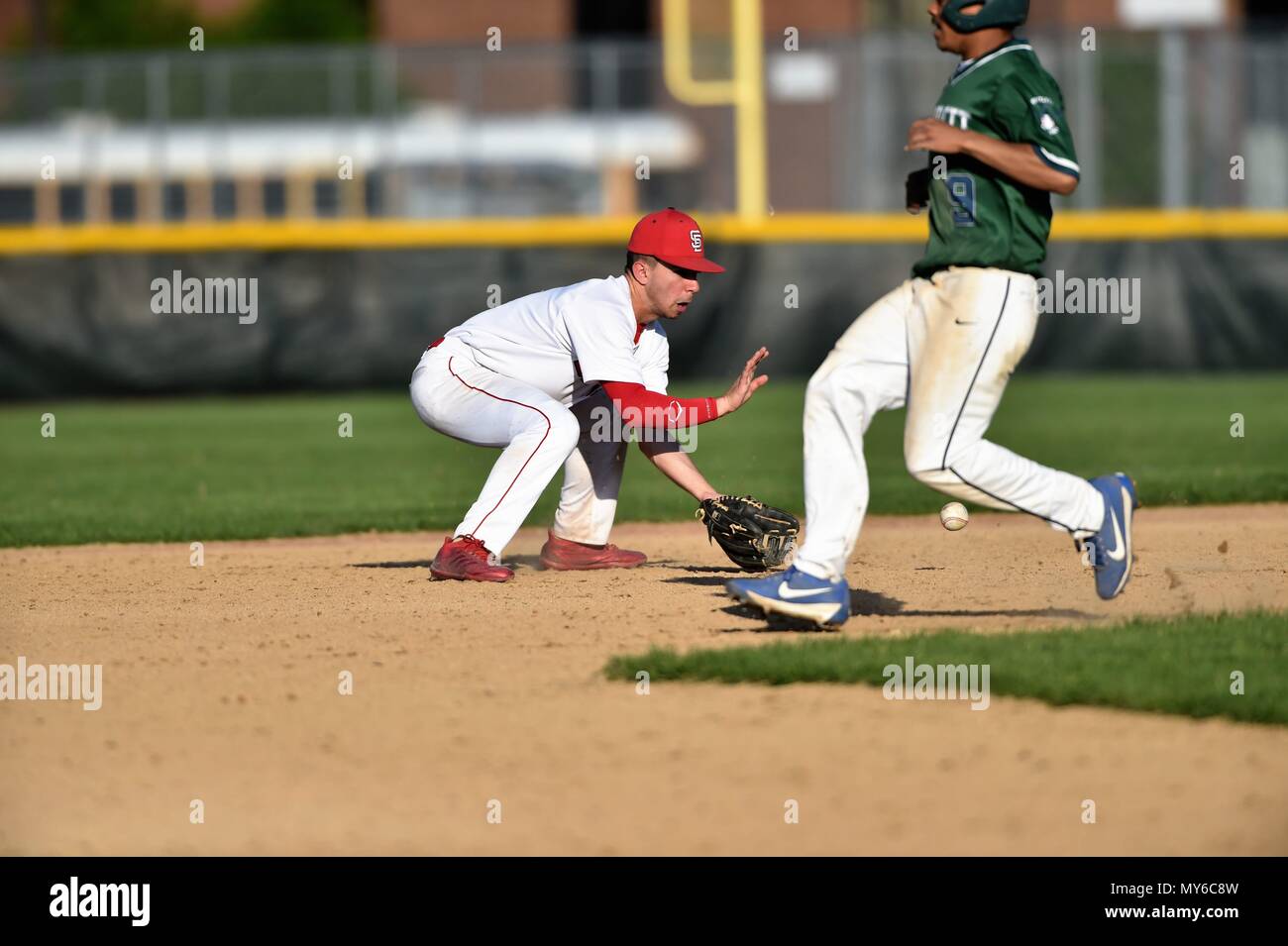 Second baseman fielding a ground ball as an opposing base runner ...
