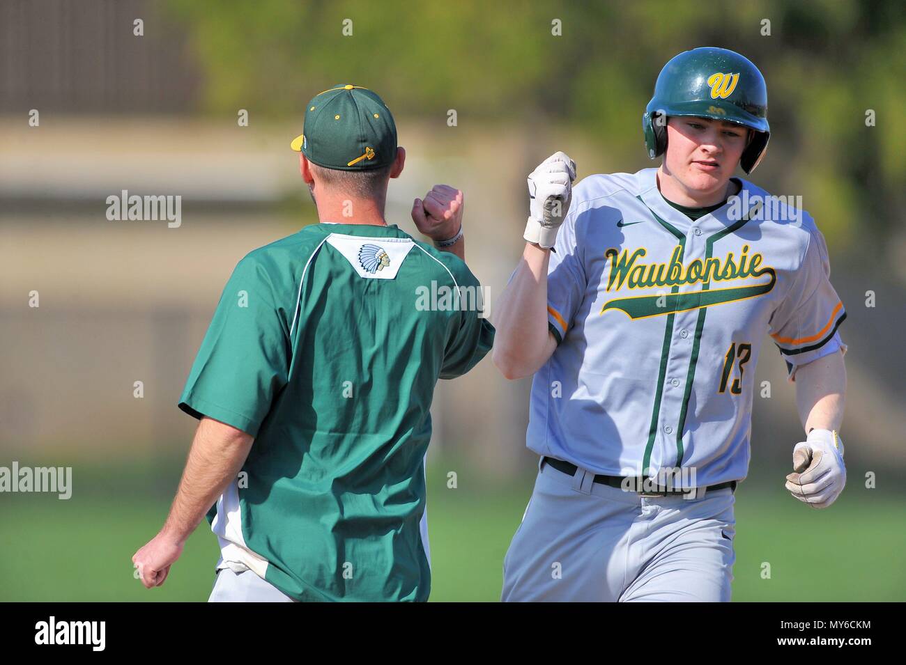 Third base coach and player exchange fist pumps as the player competes ...