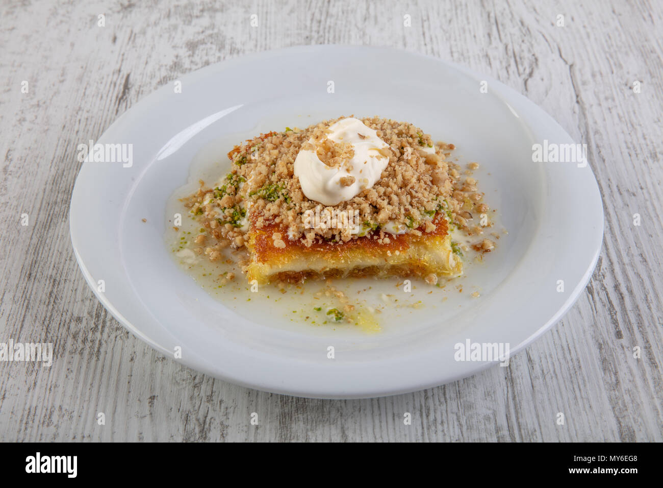 Turkish dessert kunefe on kaymak, cream slide with pistachio powder ...