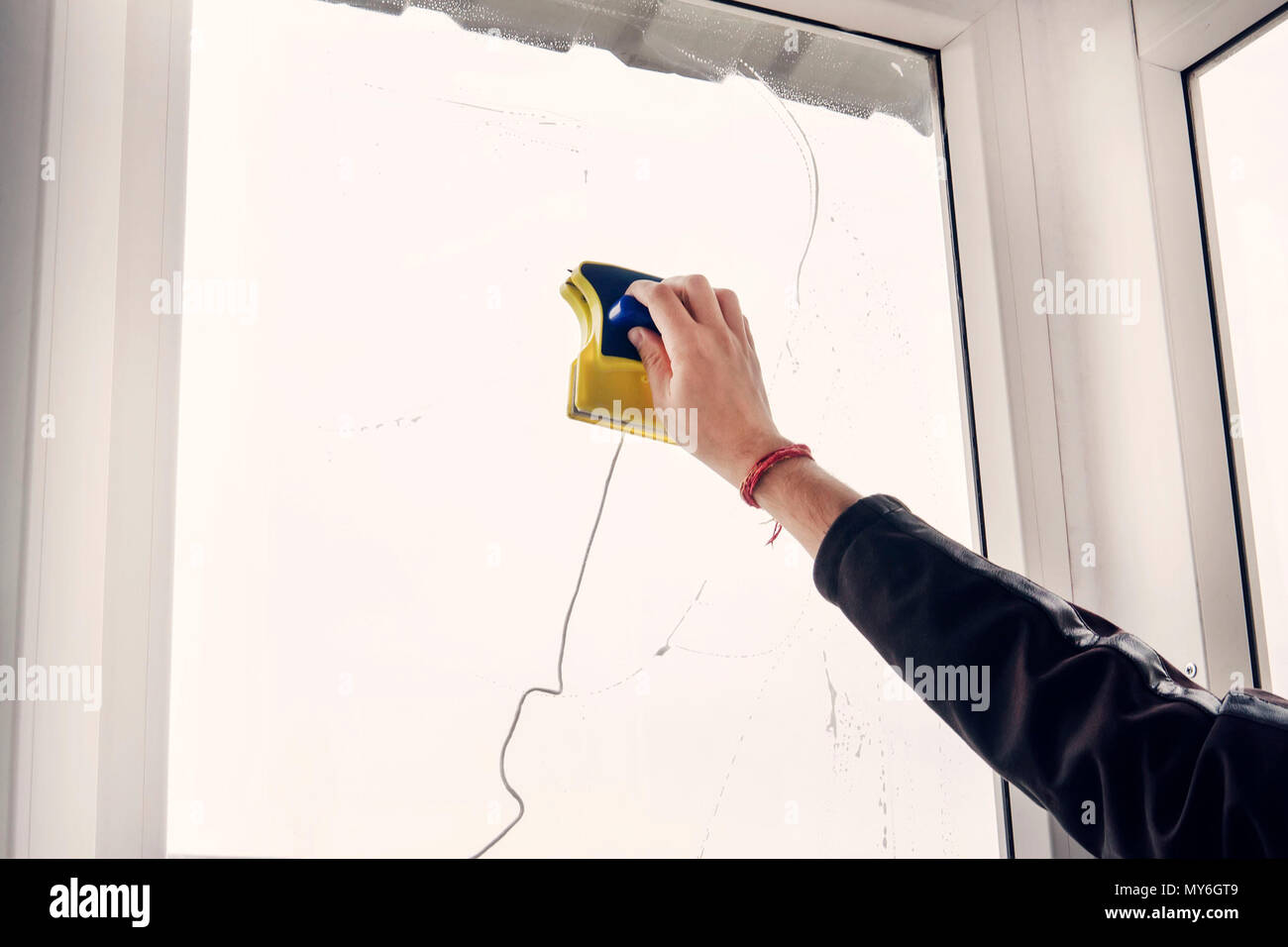 Window cleaner using a squeegee to wash a window. Washing the window ...