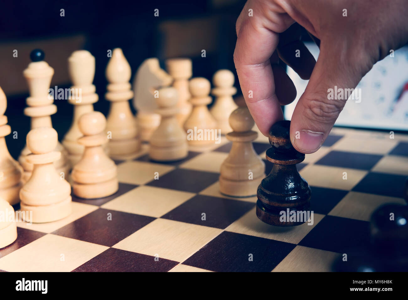 male hand playing chess on light blurred background , black pawn in the ...