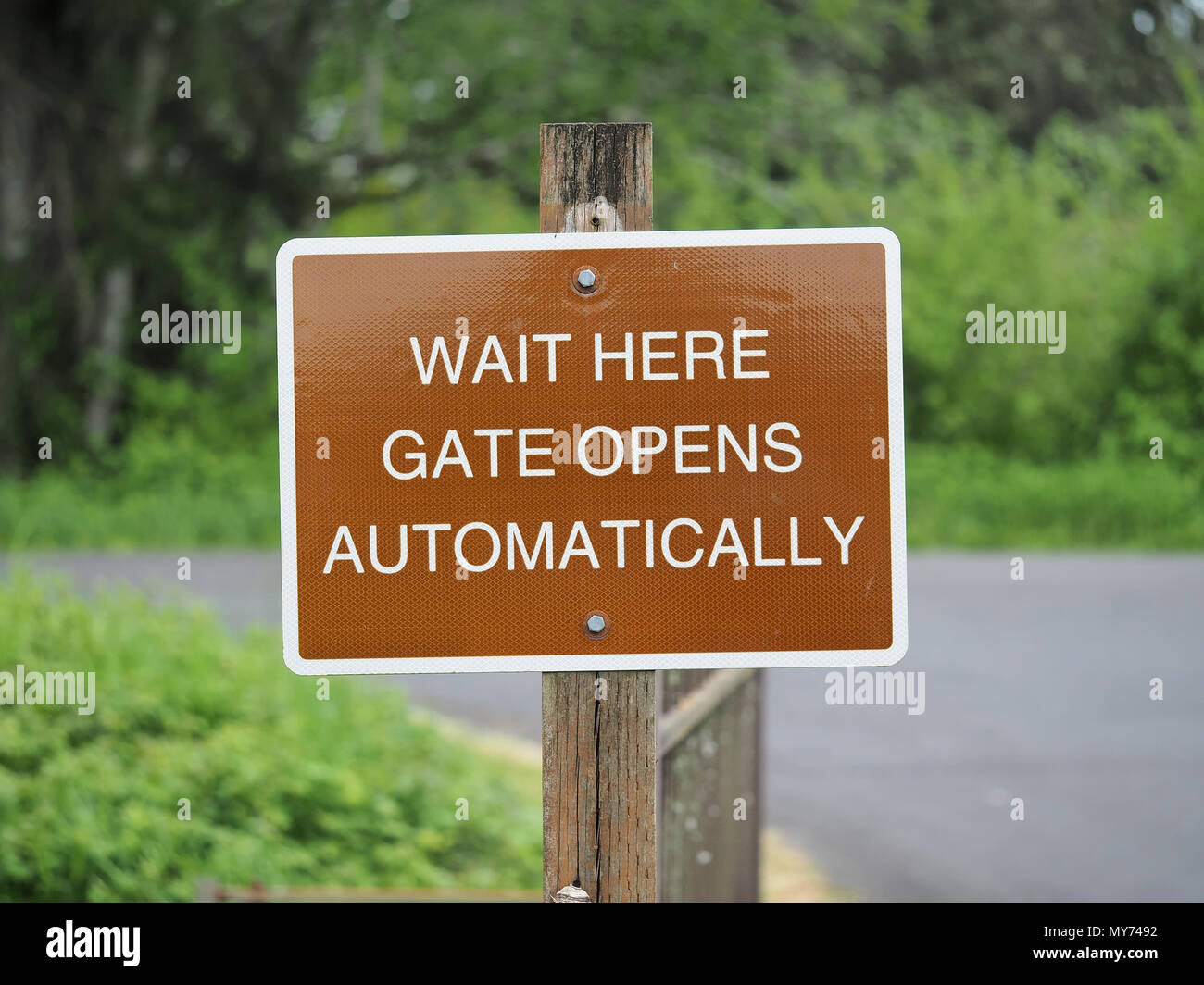 Wait here gate opens automatically sign Stock Photo - Alamy