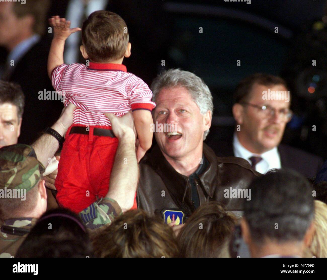 US President Bill Clinton speaking to a waving child, who is held by a ...