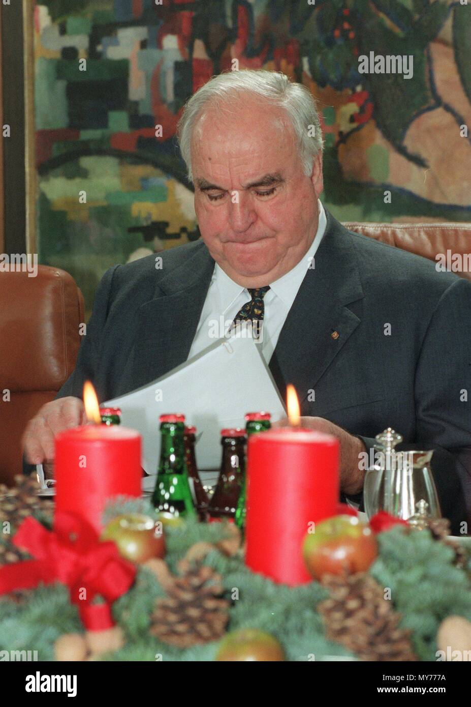 German Chancellor Helmut Kohl studies his papers at a table decorated ...