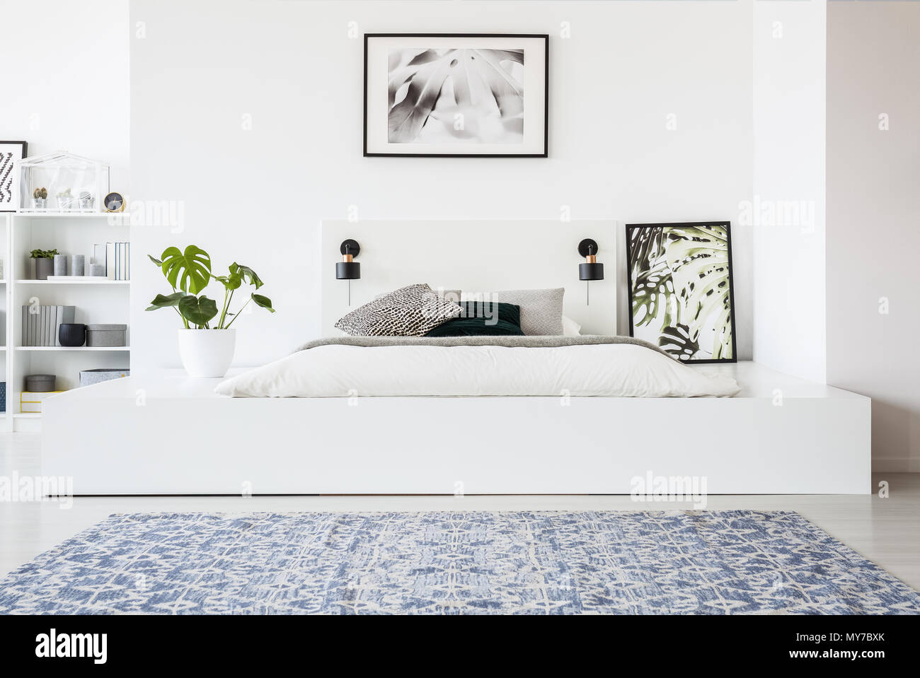 Patterned carpet and poster in white bedroom interior with plant on ...
