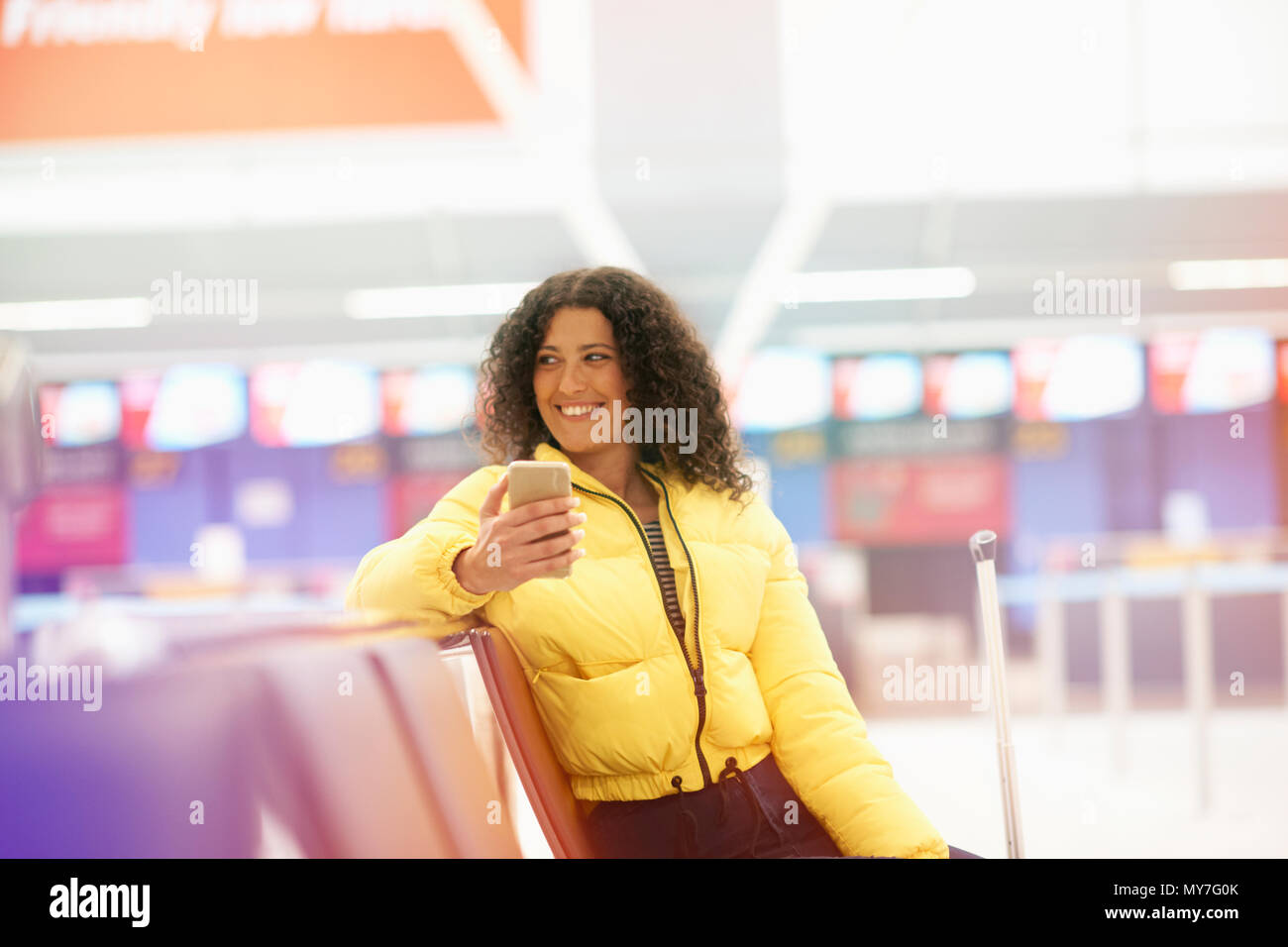 Mid adult woman looking over her shoulder in airport departure lounge ...