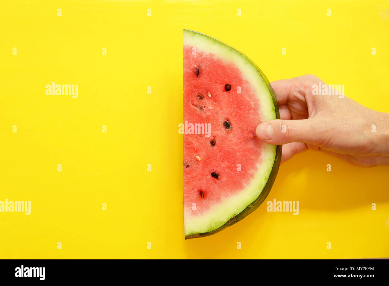 hand holding watermelon slice on yellow background Stock Photo - Alamy