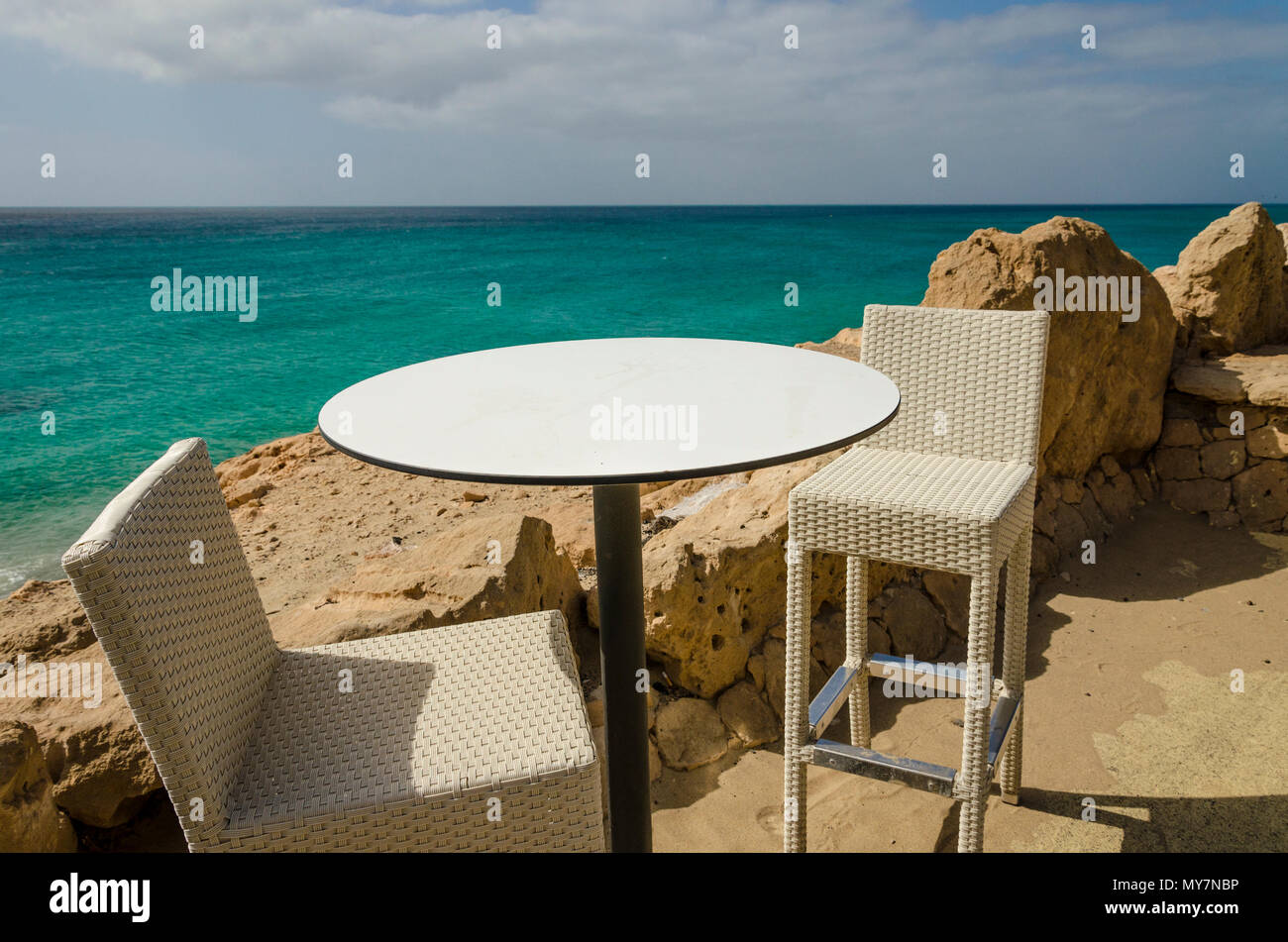 Cafe bar with a sea view. Two white bar chairs and a table on a ...