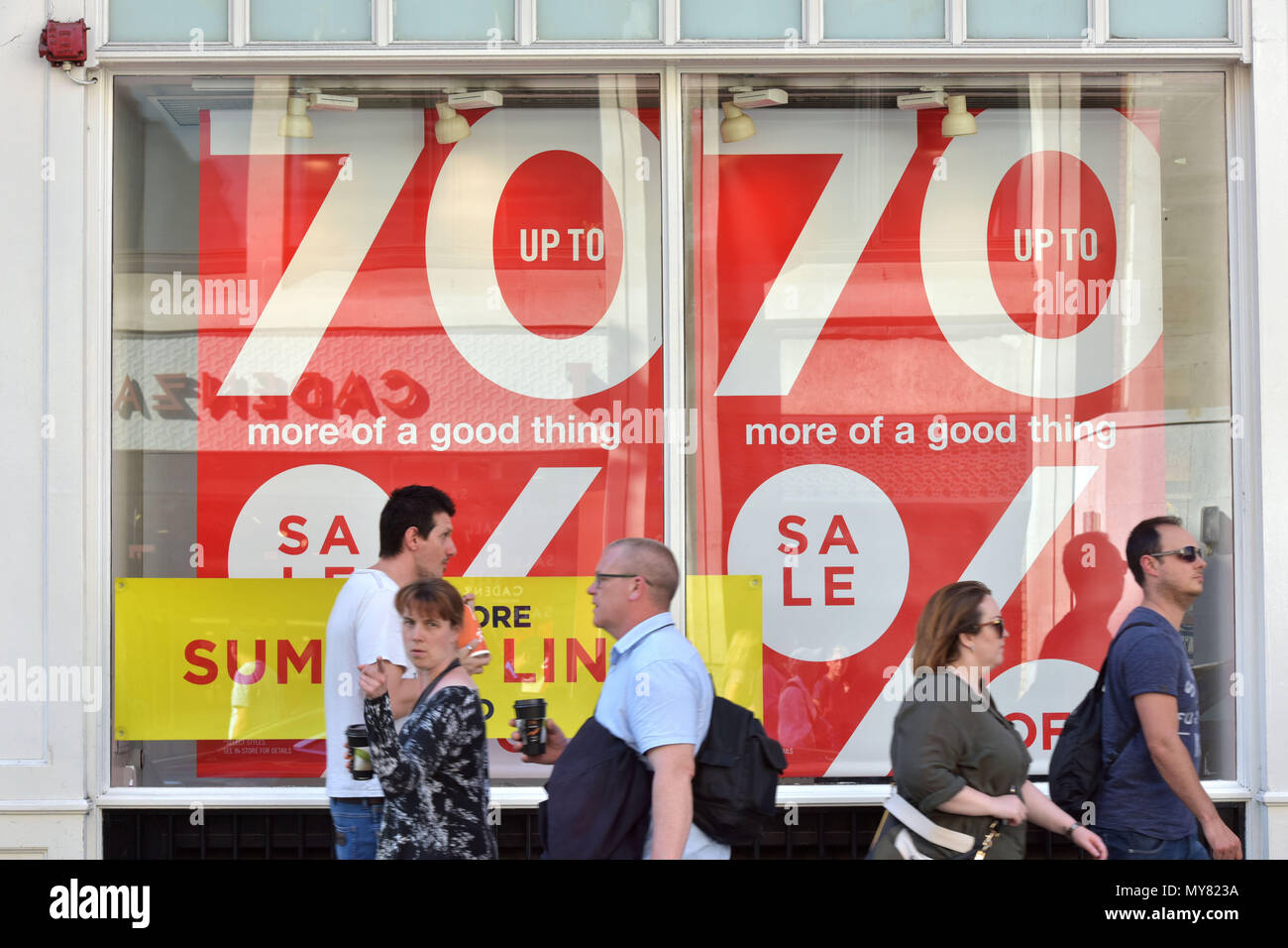 Tourists and shoppers walk past the shops with 70% further reduction ...