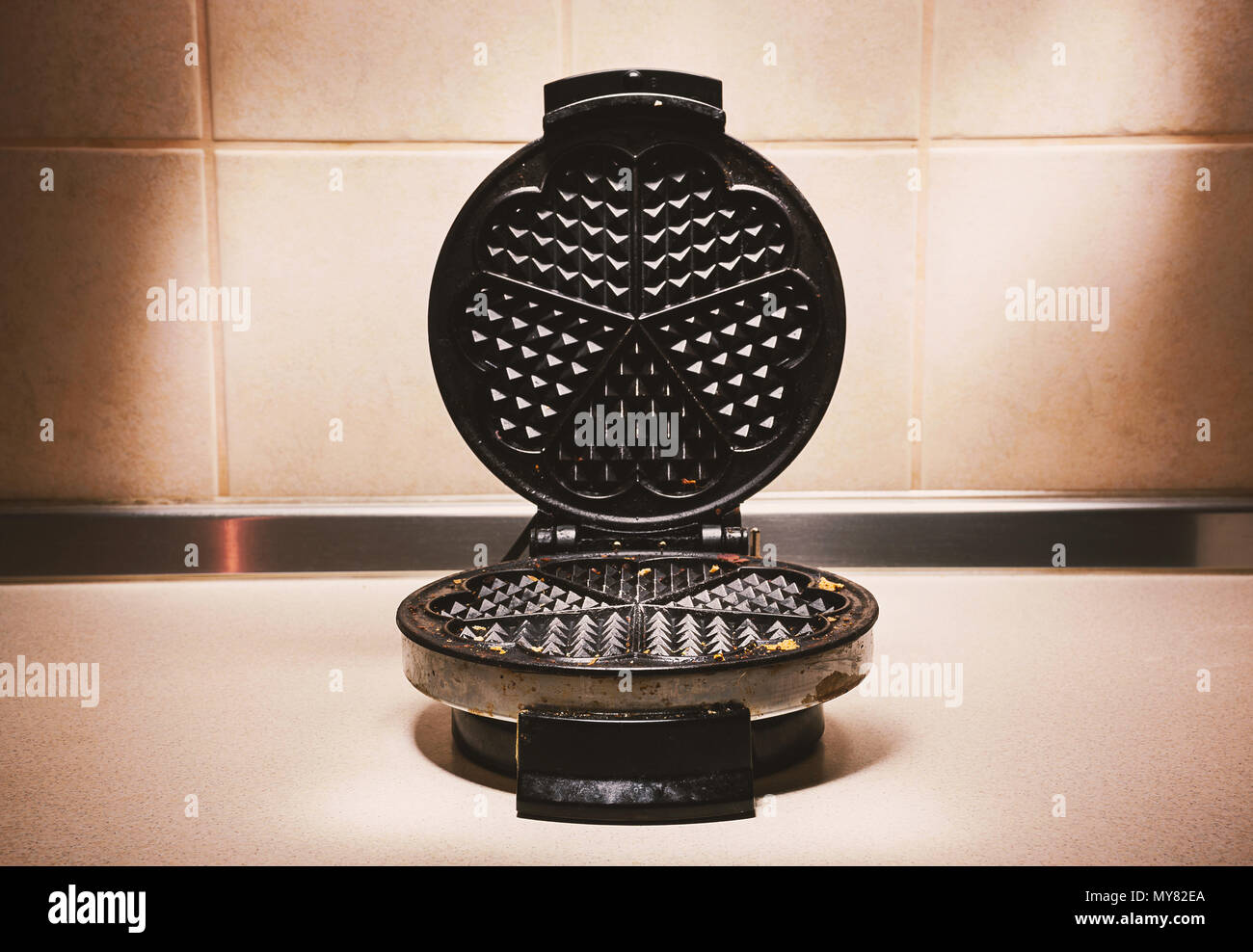 Old and dirty electric kitchen press, open on desk ready for preparing ...