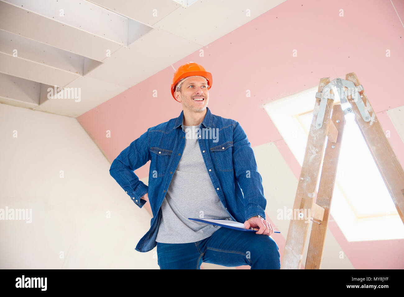 Portrait of construction worker standing on the ladder at the ...