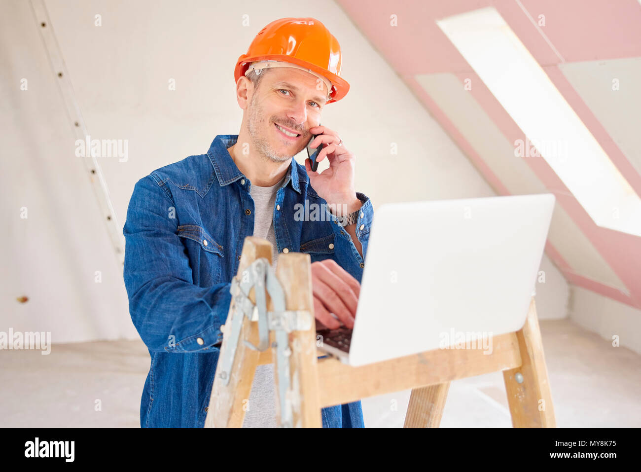 Portrait of happy construction worker using mobile phone and consulting ...
