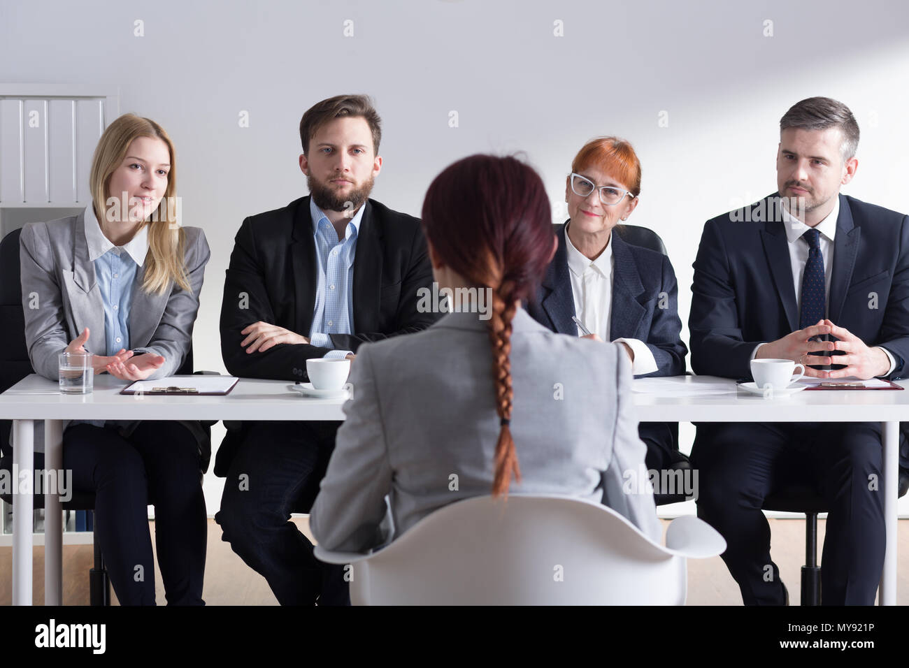 Woman during job interview and four businesspeople sitting by office ...